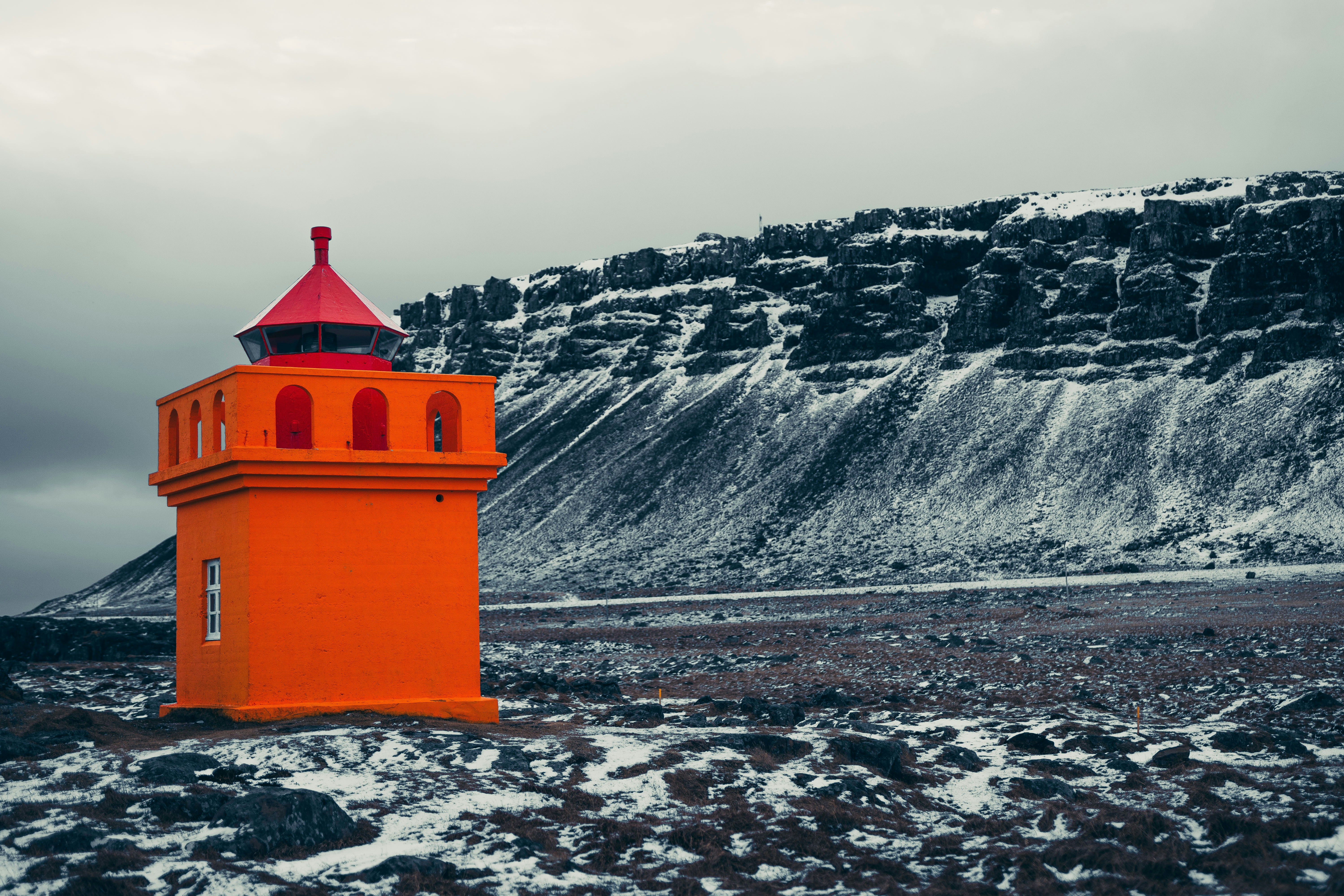 A bright orange lighthouse on a rocky beach photo – Free Izland Image ...