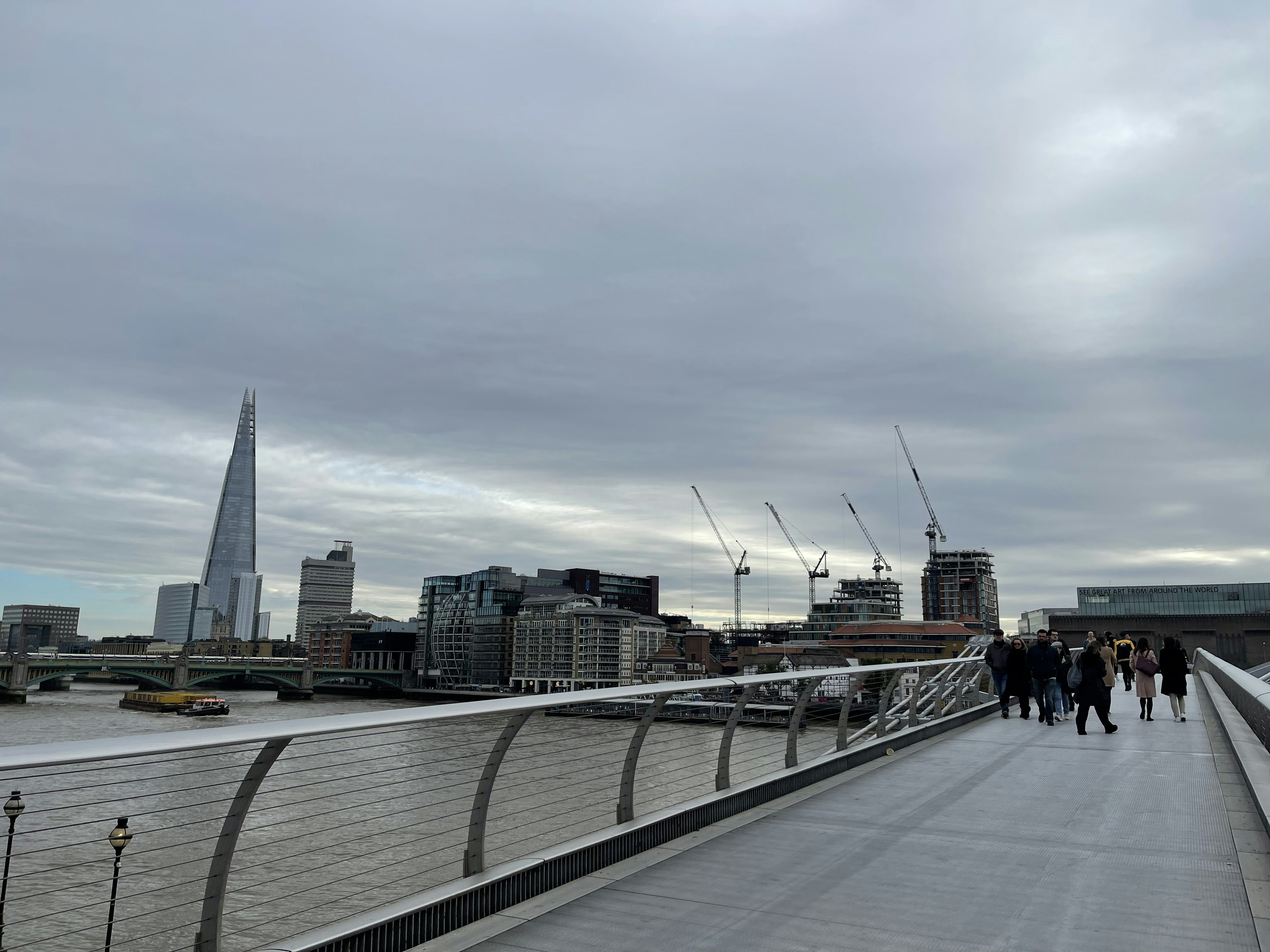Overcast Thames Crossing: Footsteps Under The Shard and Crane-Lined Skyline