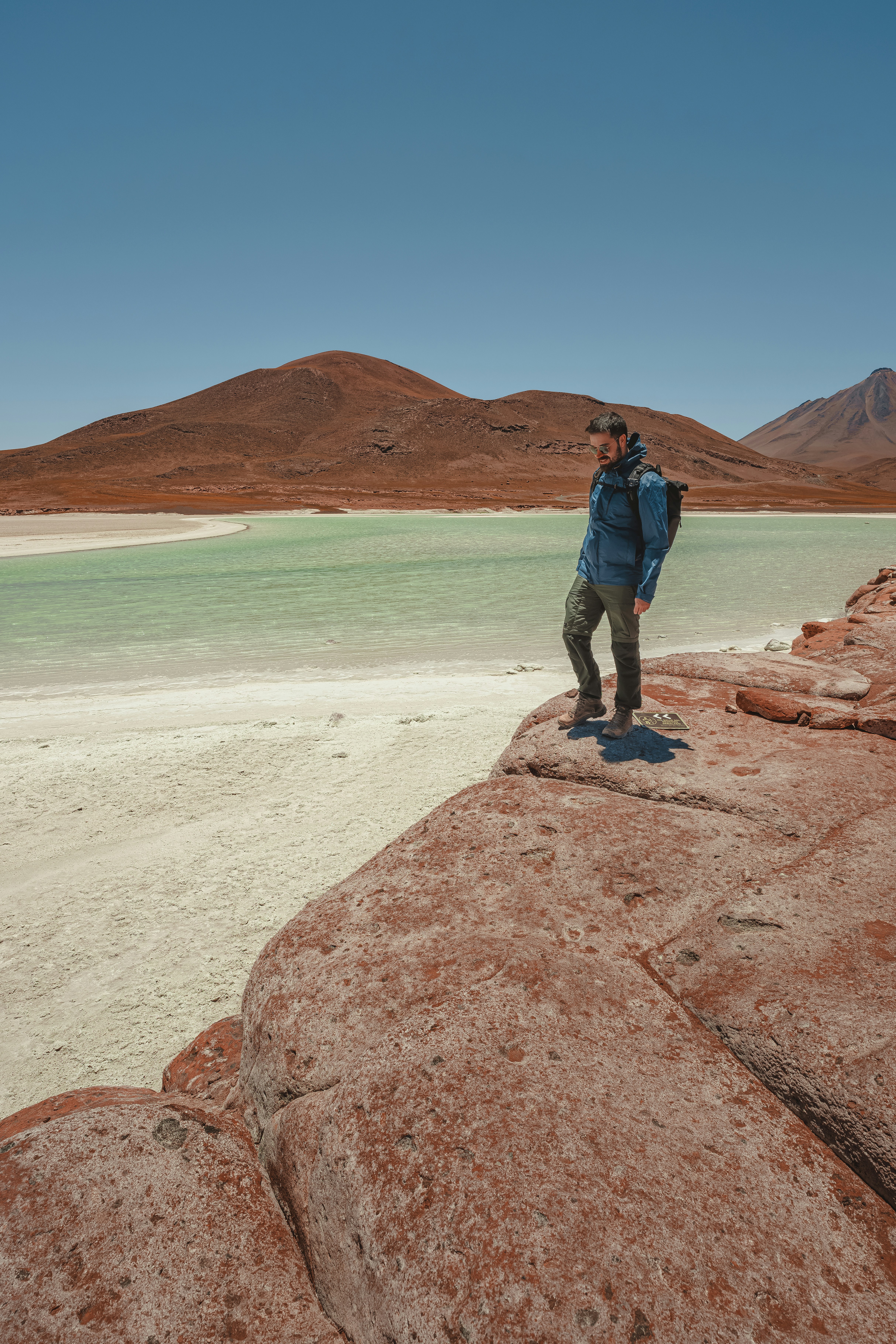 Foto Un hombre parado en la cima de una gran roca junto a un cuerpo de ...