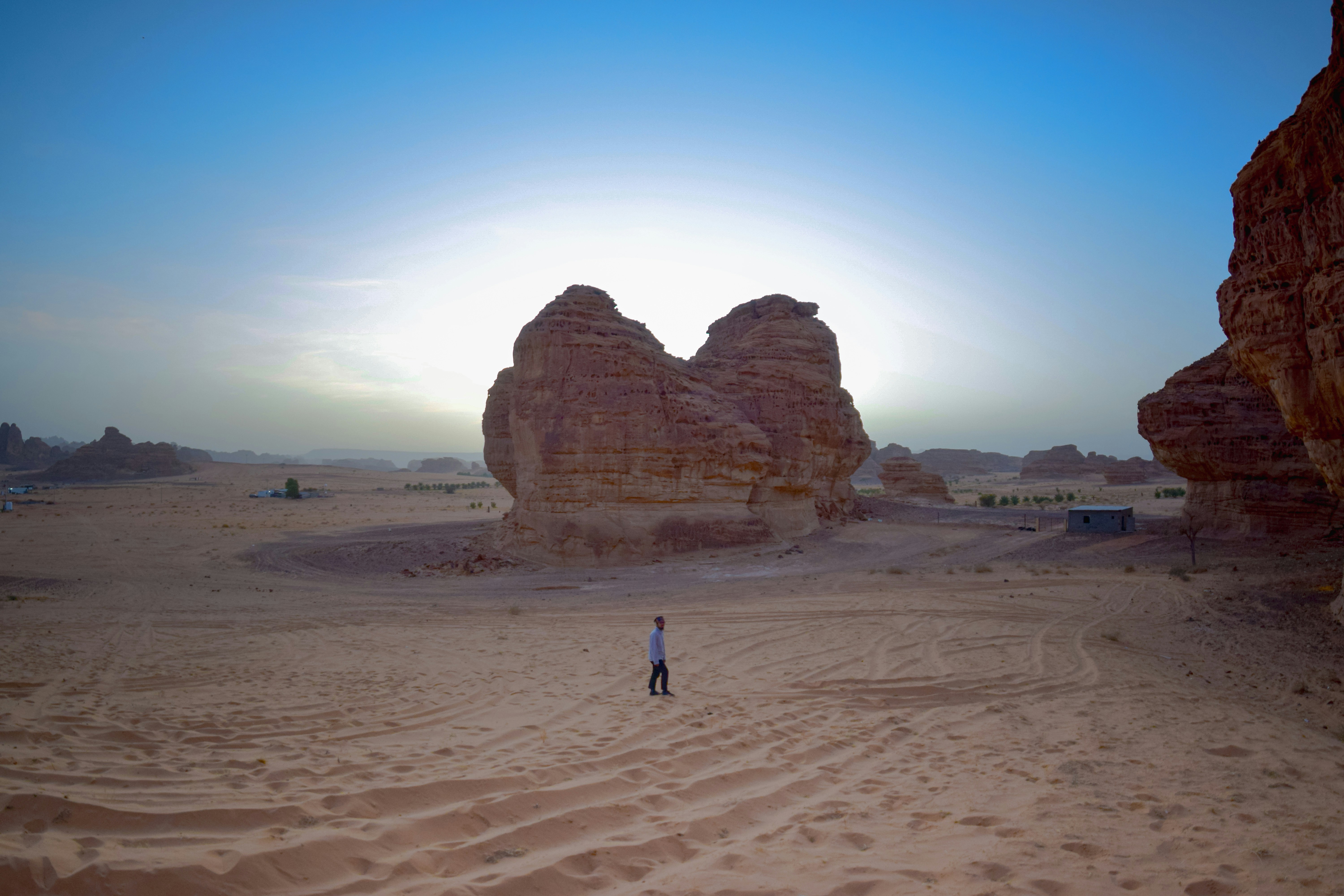 Lone Wanderer Beneath Twin Desert Monoliths at Dawn
