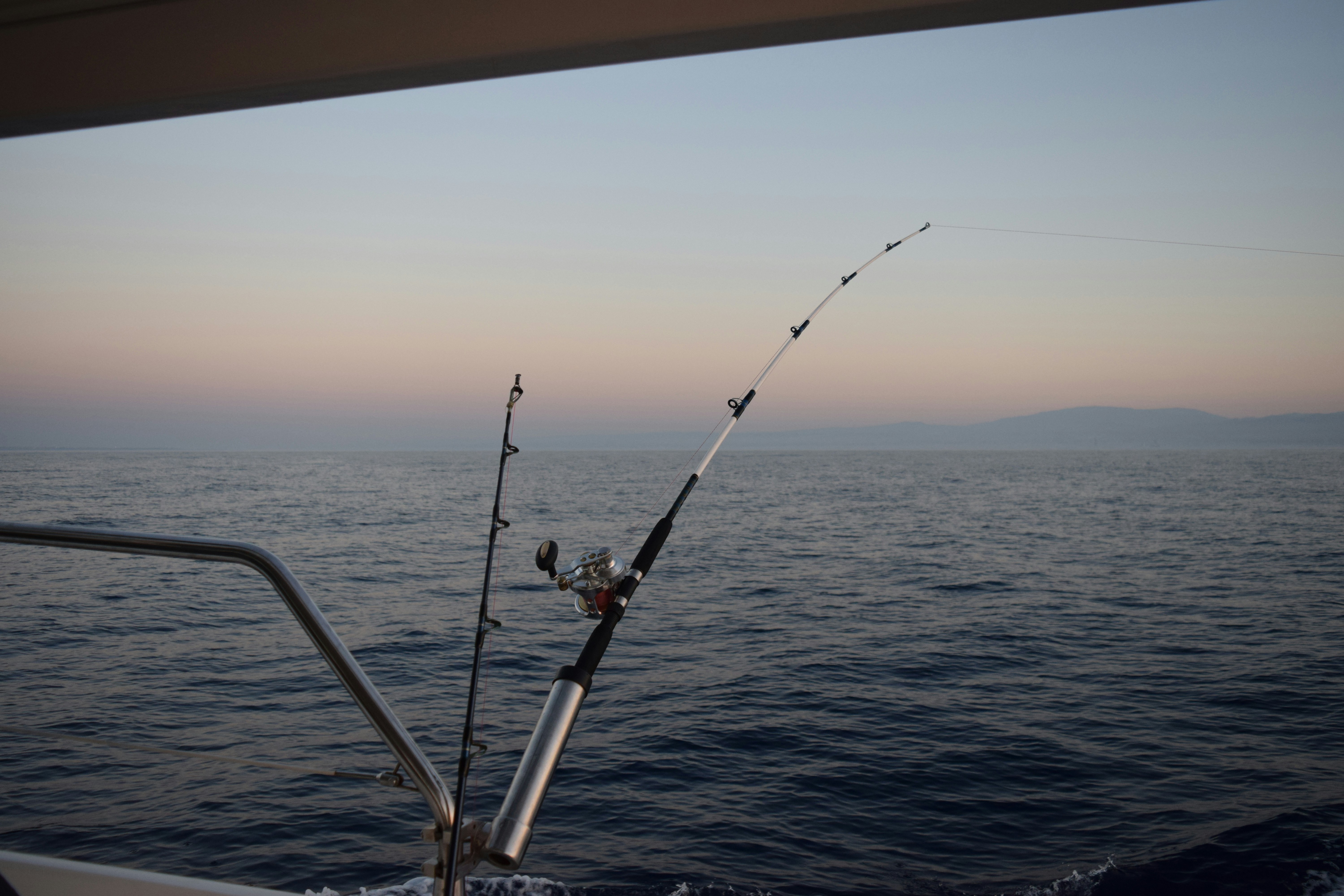 Two fishing rods on a boat in the ocean photo – Free Grey Image on Unsplash