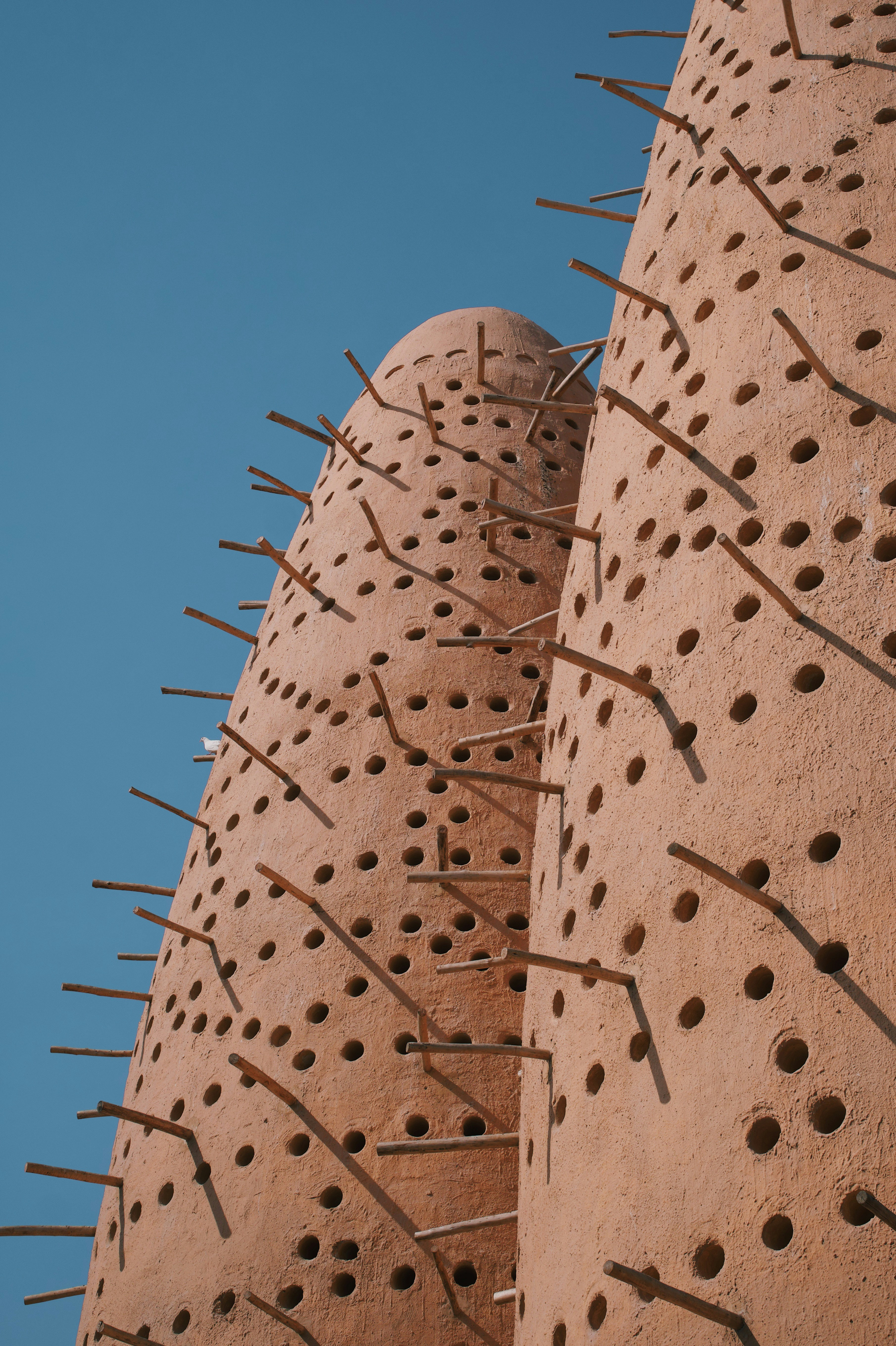Sunbaked adobe towers pierced with rusted rebar against a cobalt sky