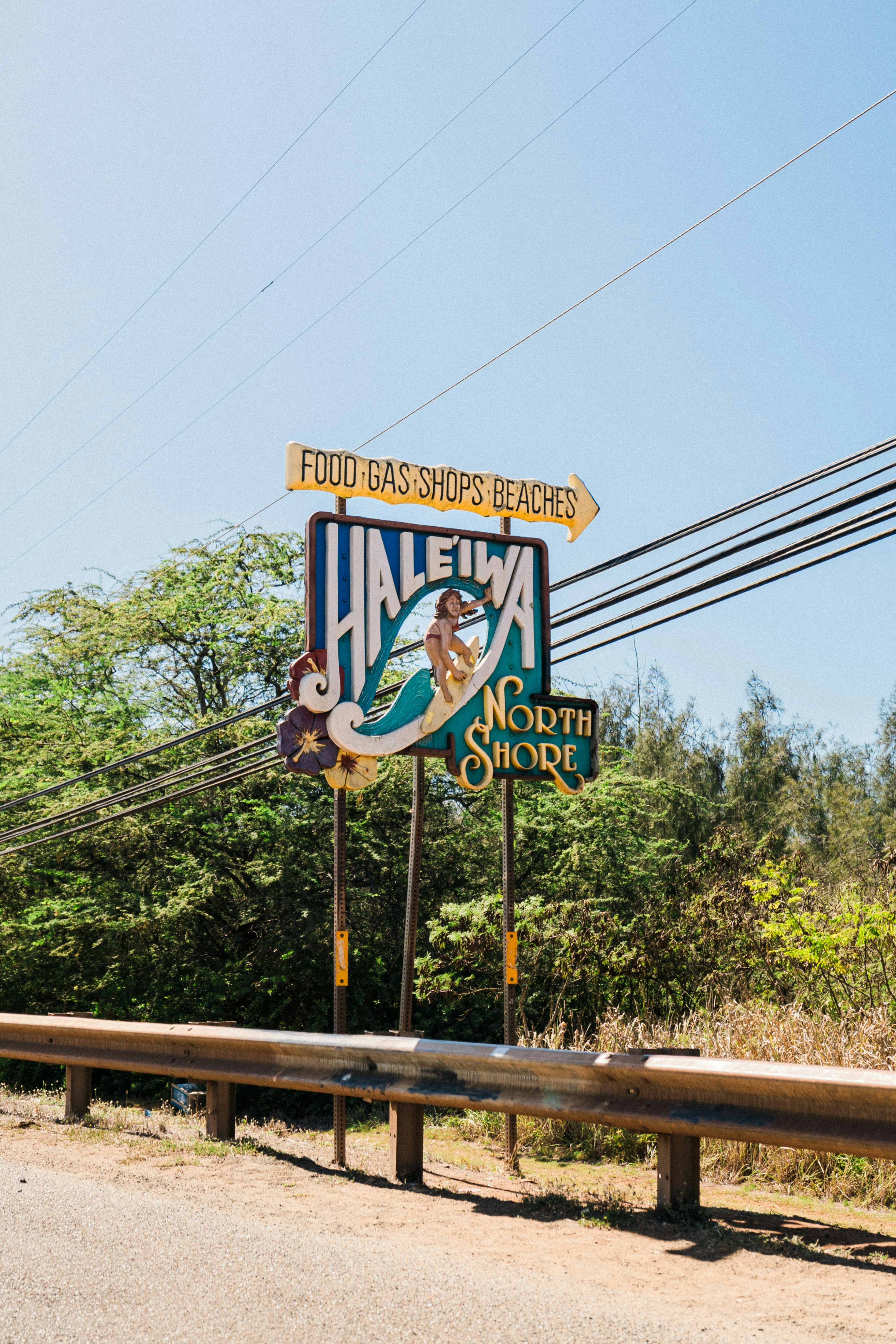 Colorful signpost directing travelers to Haleiwa, North Shore, highlighting nearby amenities like food and beaches.