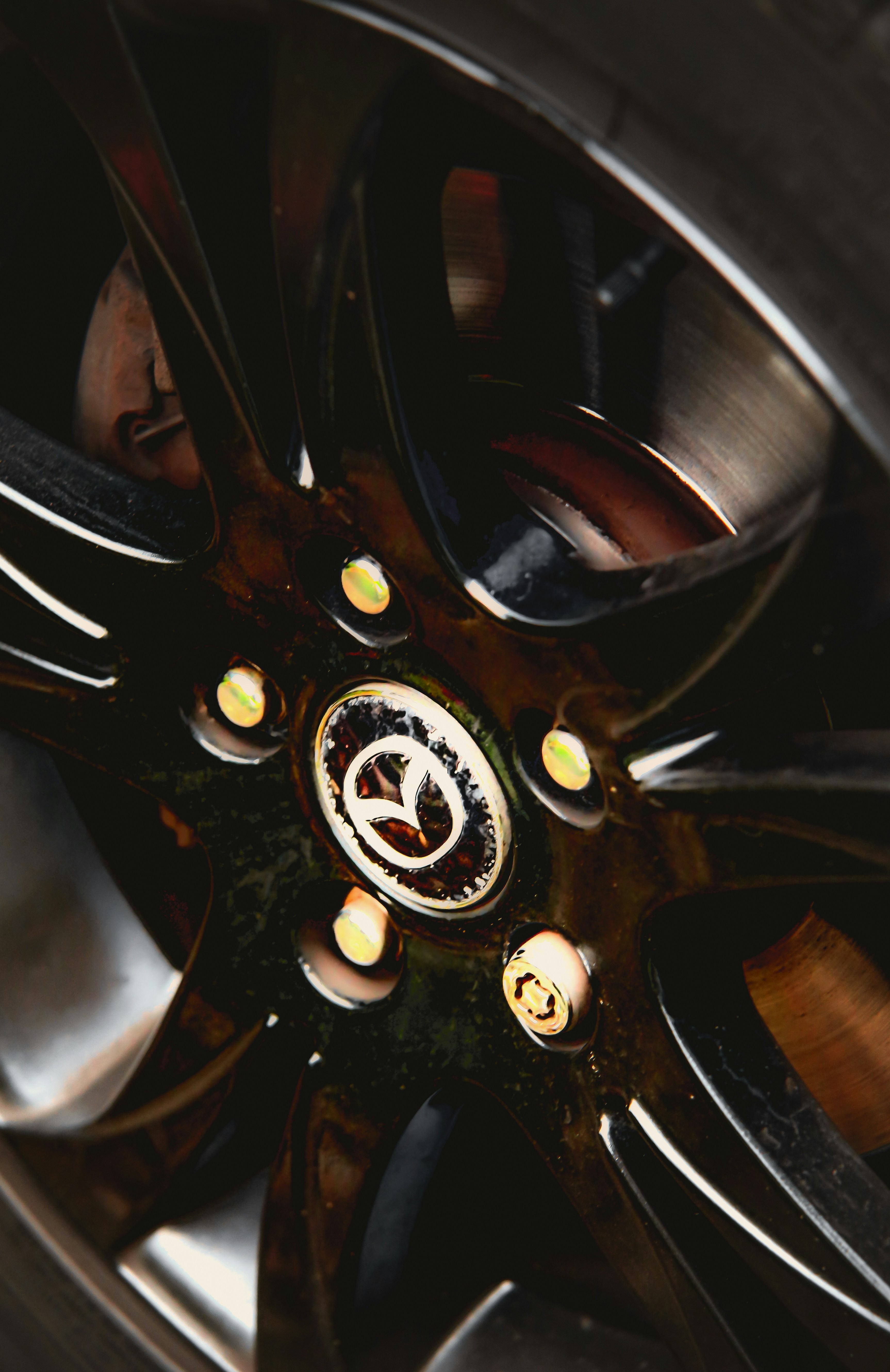 Macro Portrait of a Mazda Wheel Center: Glossy Spokes Meet a Weathered Emblem