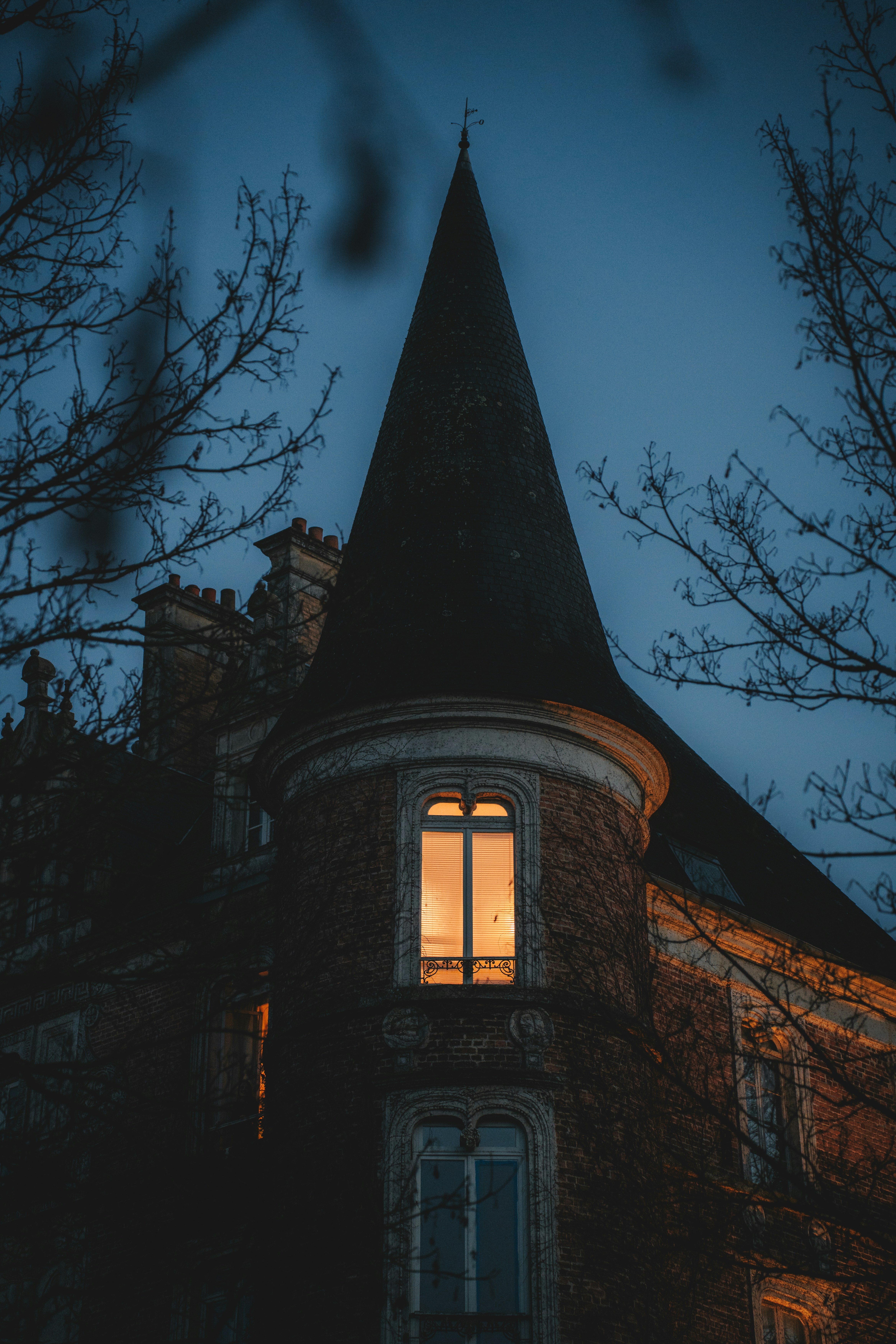 A building with a tower with a lit up window photo – Free Blue Image on ...