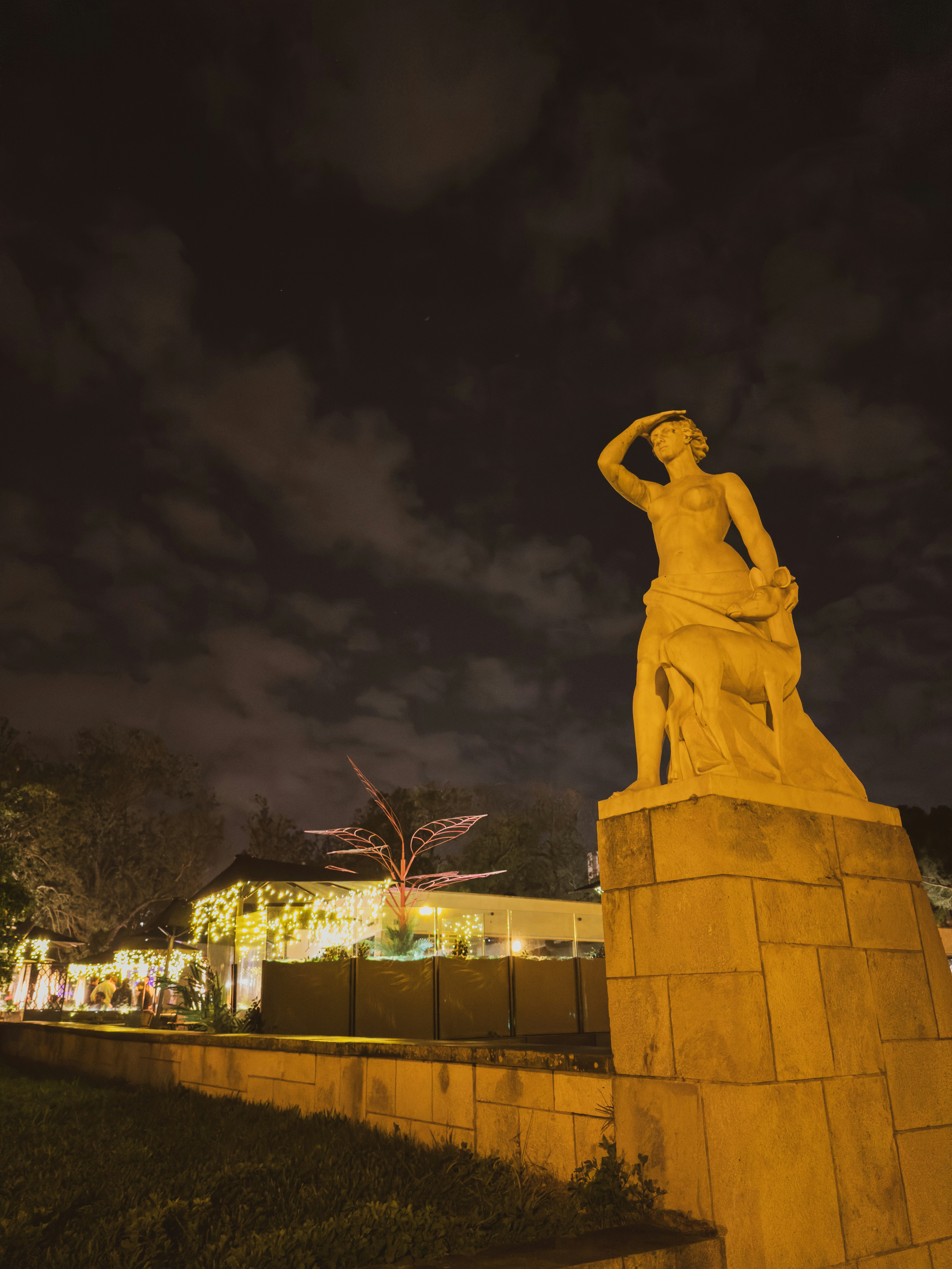 Amber Guardian at Night: A Marble Statue Bathed in Warm Plaza Light
