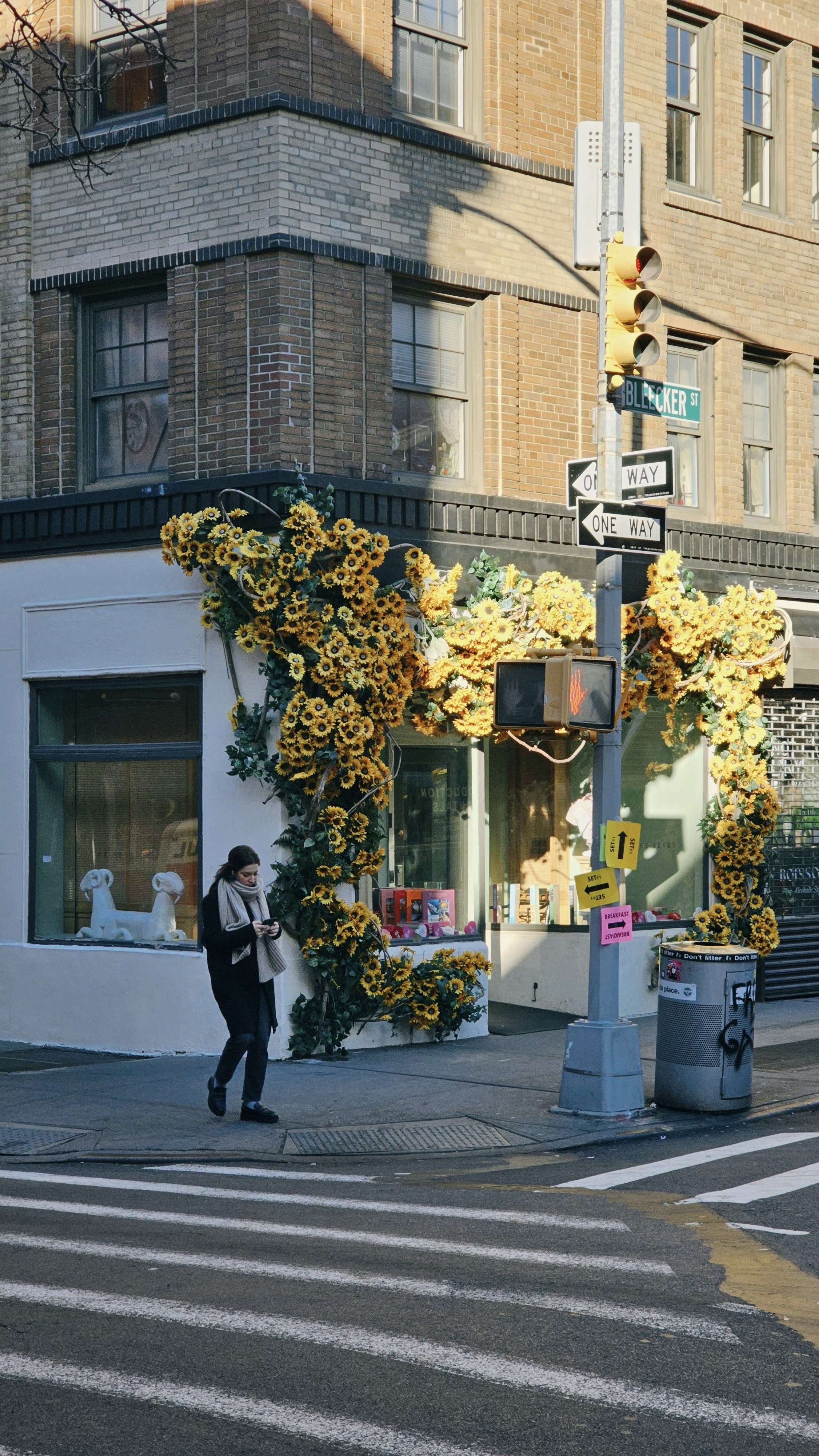 Daylight street photograph of a storefront framed by a large sunflower arch at a city corner.