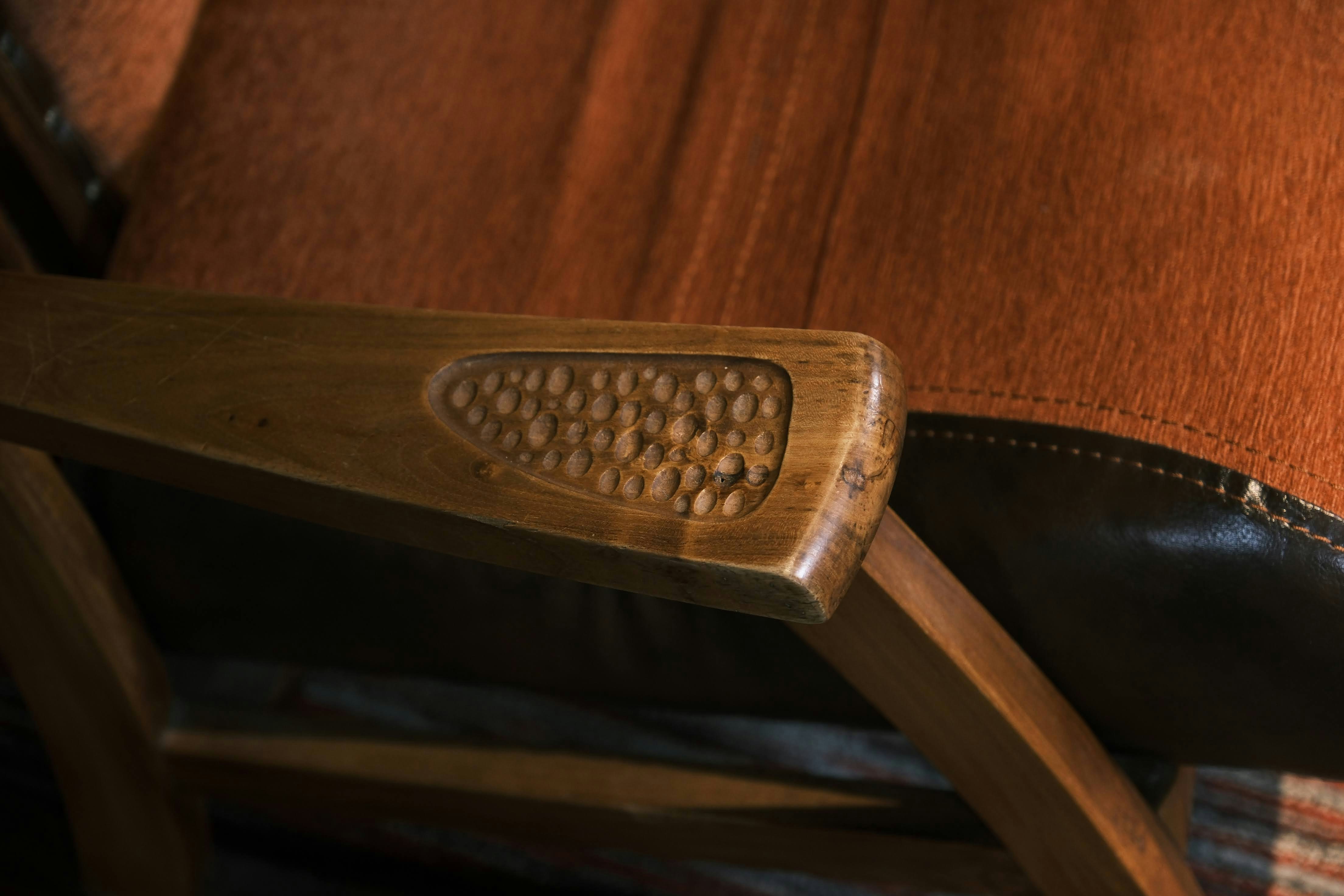 Carved Wood and Pebble Texture: Close-Up on a Leather-Trimmed Chair Armrest