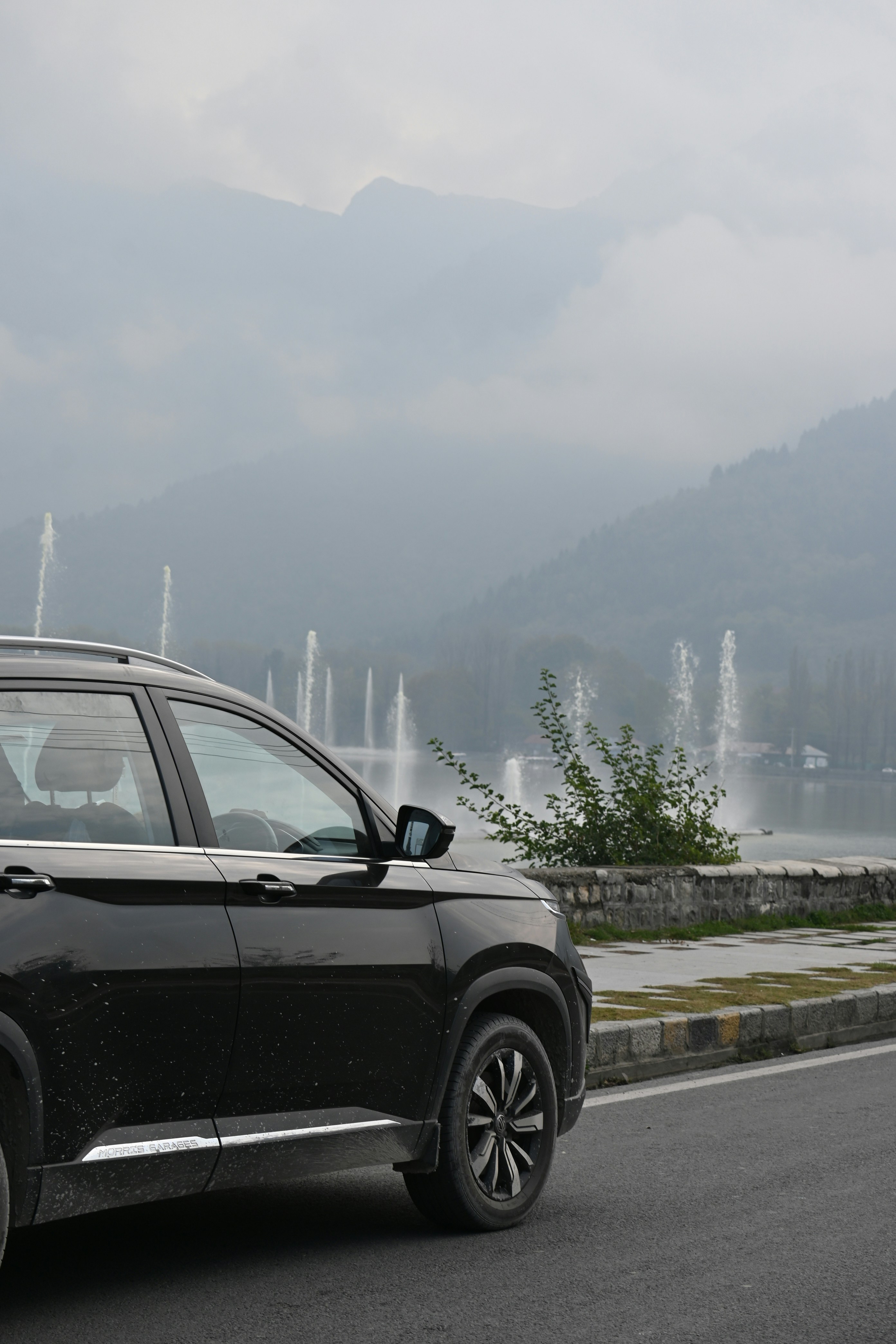Pause by the Lake: A Black SUV Framed by Fountains and Mist