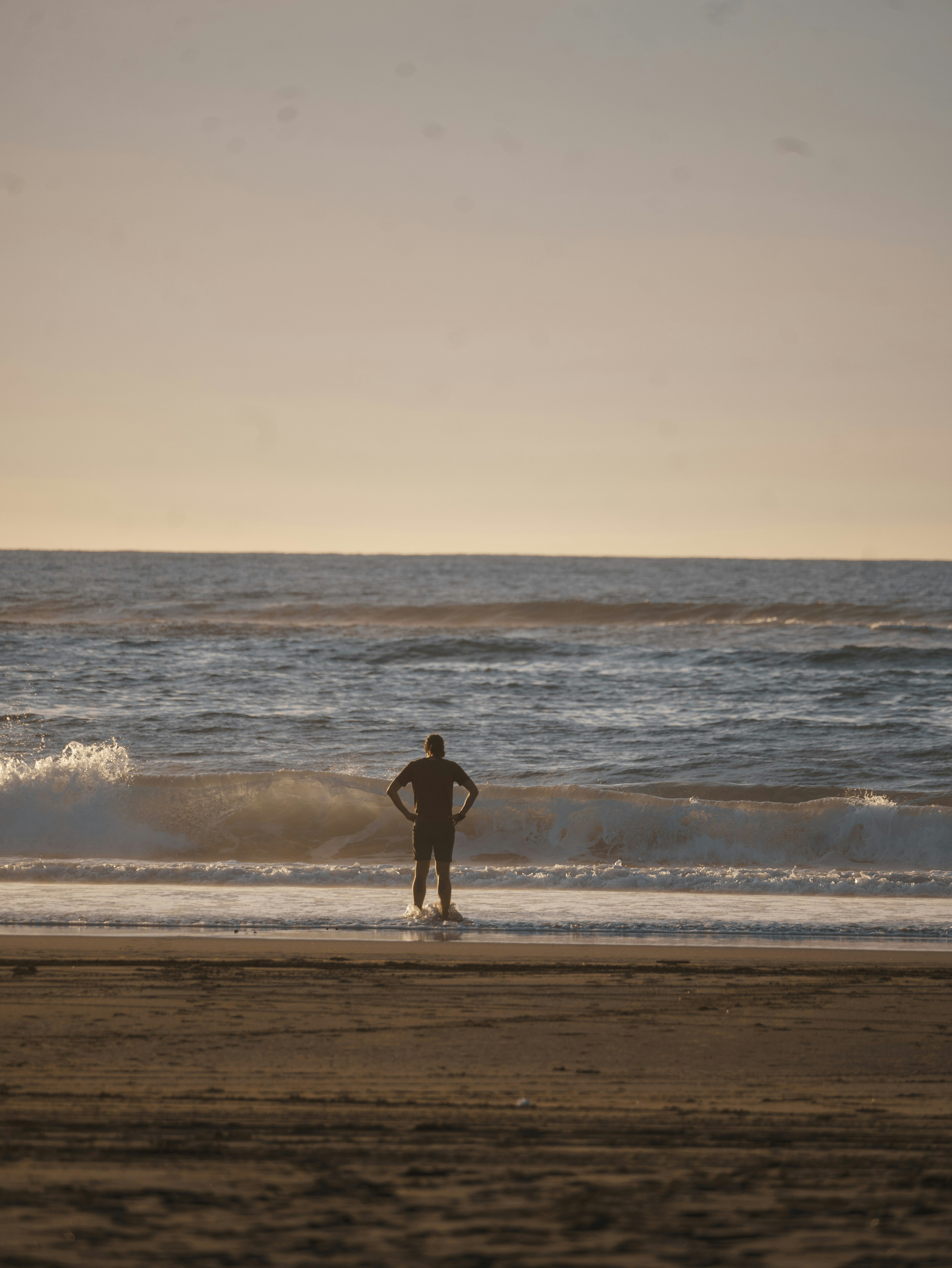 Lone silhouette at the shoreline during golden hour