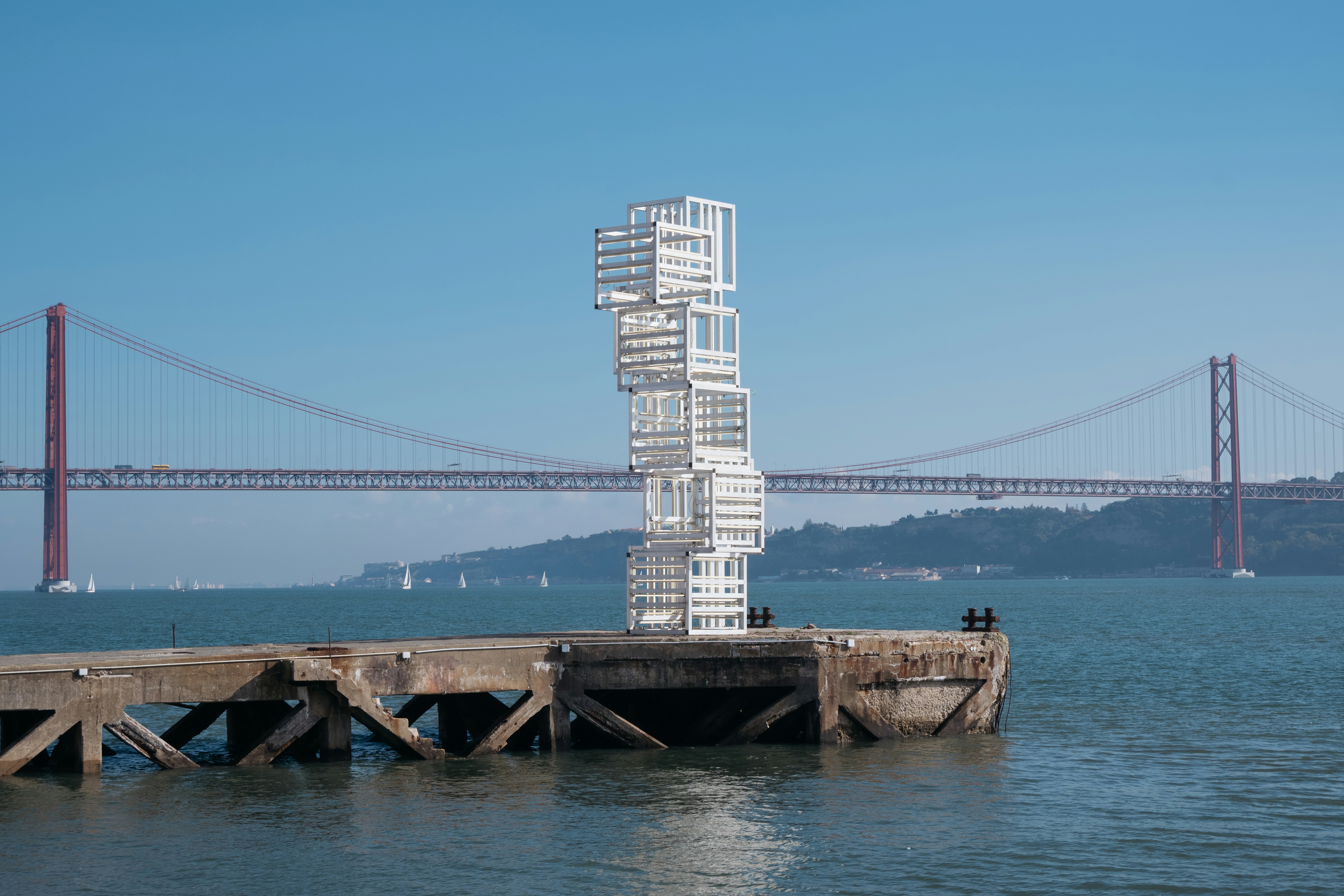 Stacked Crate Architecture on a Pier with a Distant Bridge
