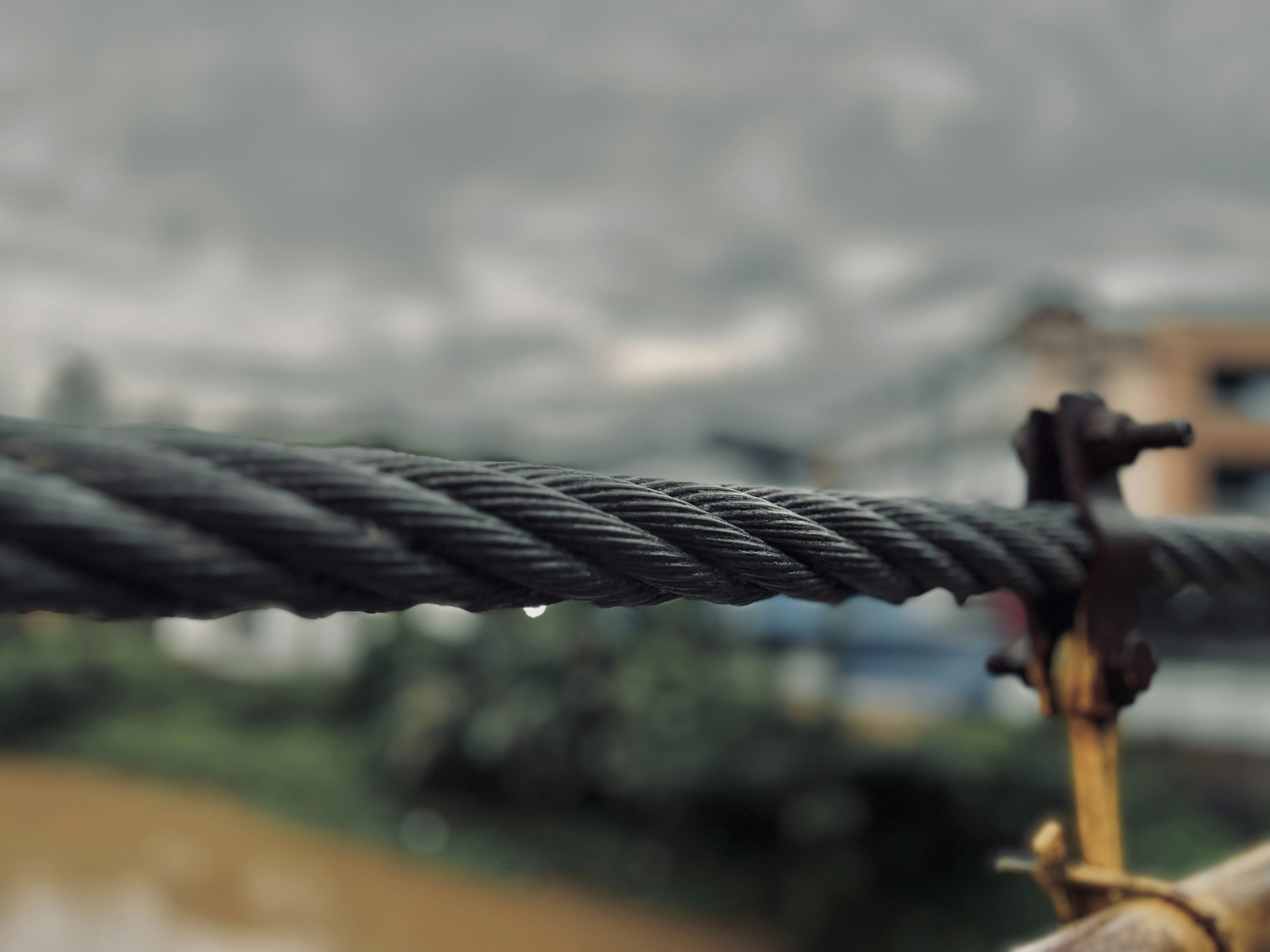Rope Tension at the Edge: Close-Up of a Weathered Cable Against a Blurred Riverside