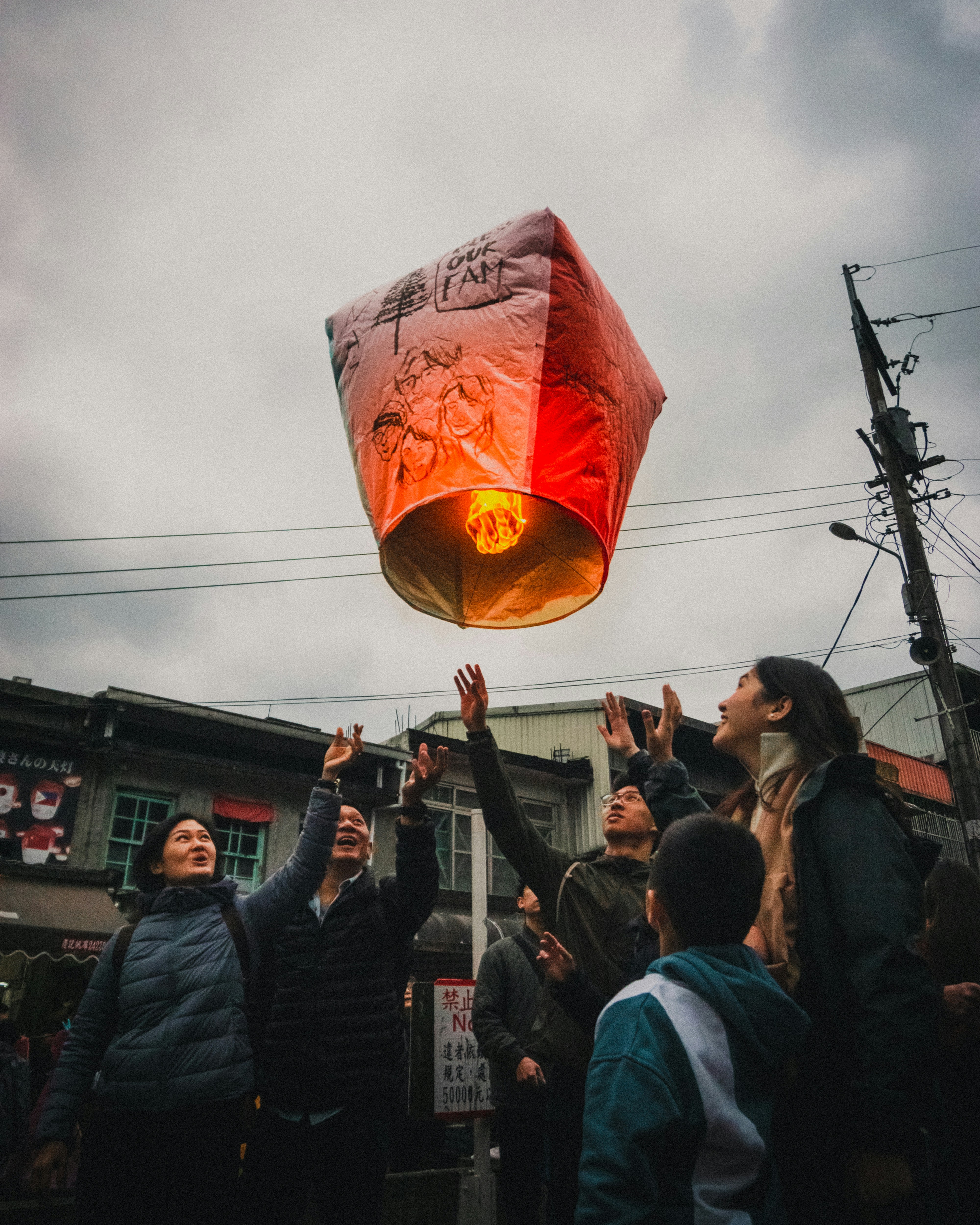 a group of people standing around a red lanternJun Hong Tan