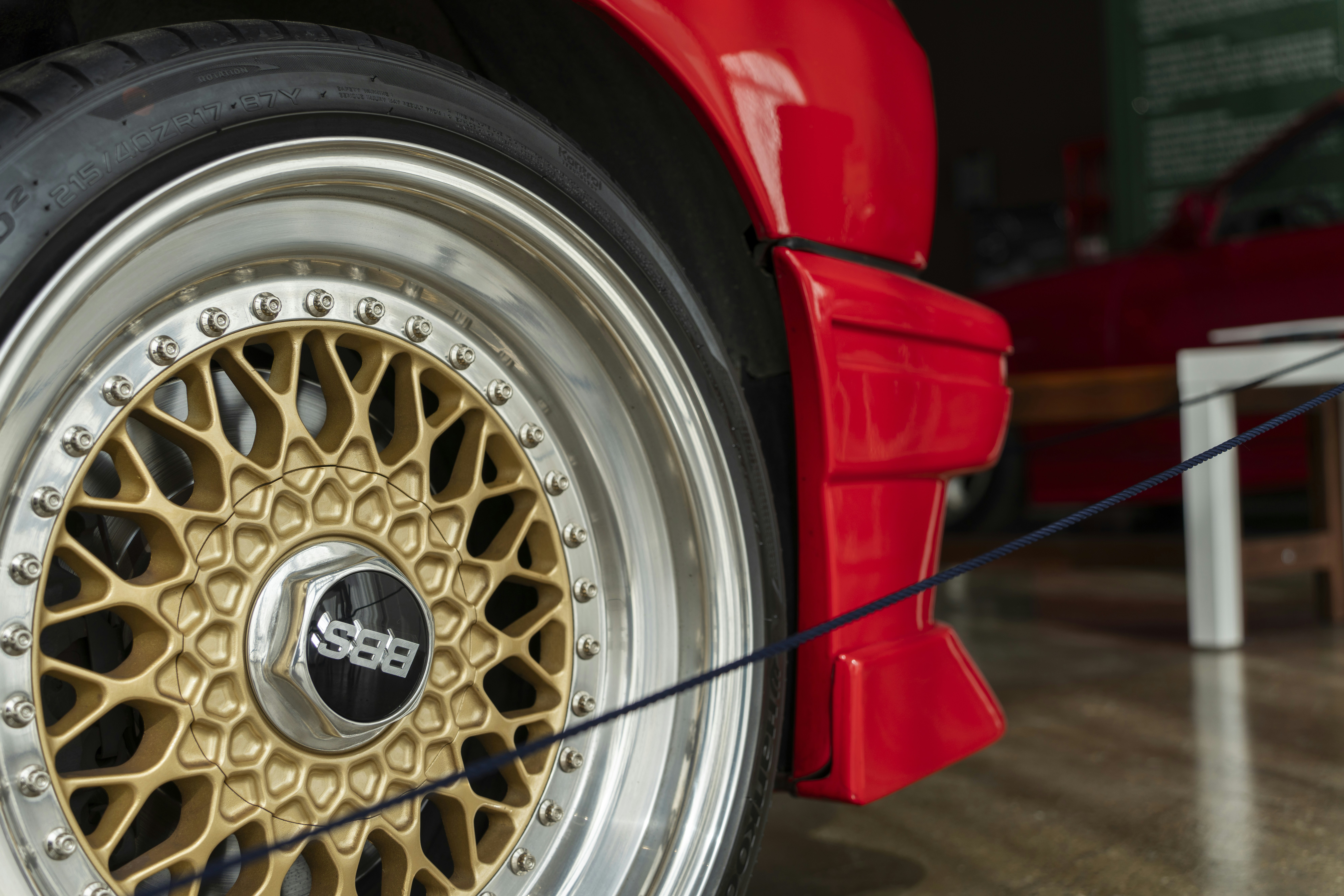 Gold BBS Lattice Wheel Close-Up Against a Glossy Red Car Body