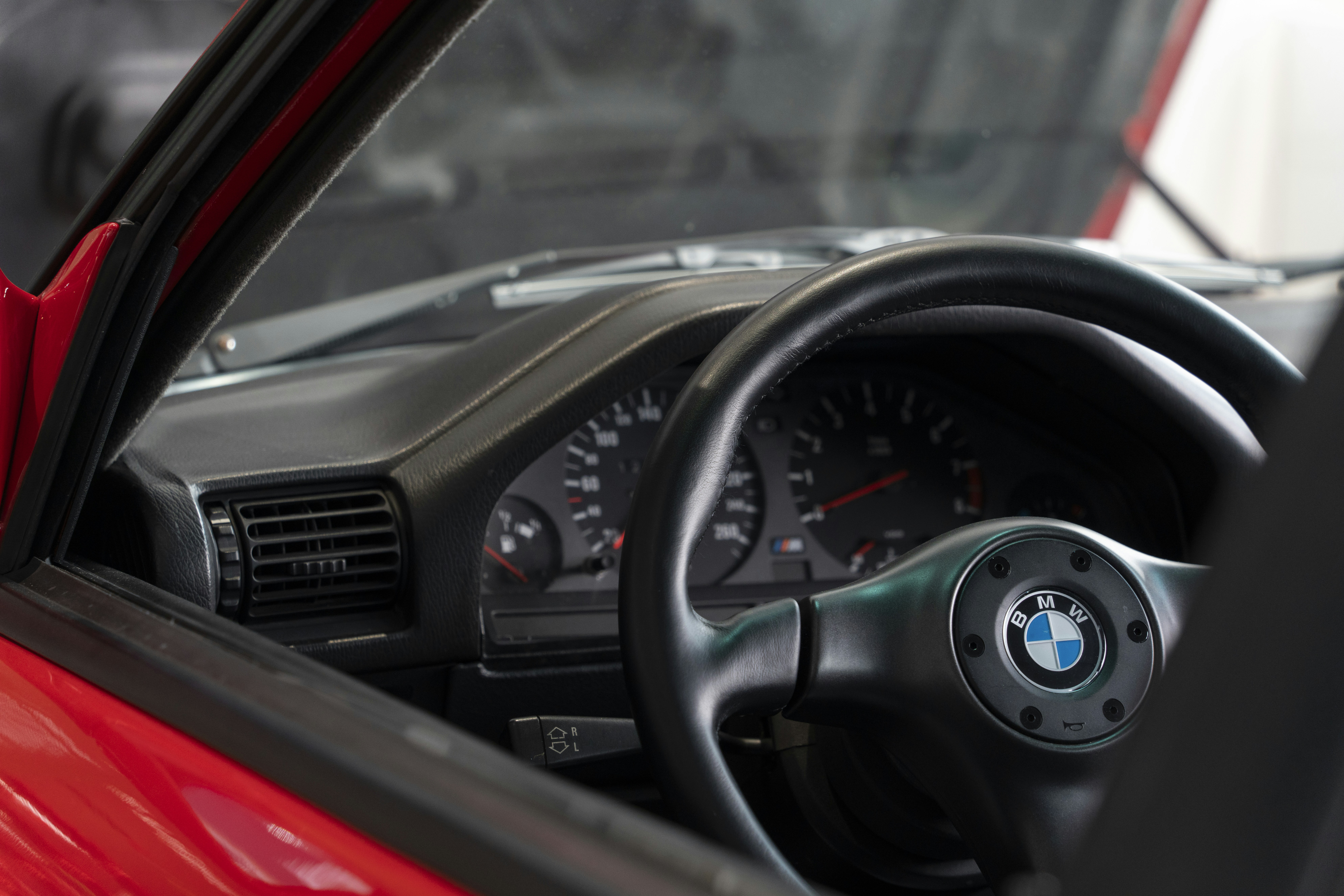 Interior view of a classic BMW dashboard featuring a sleek steering wheel and instrument panel. The focus highlights the craftsmanship and design of the vehicle's cockpit.