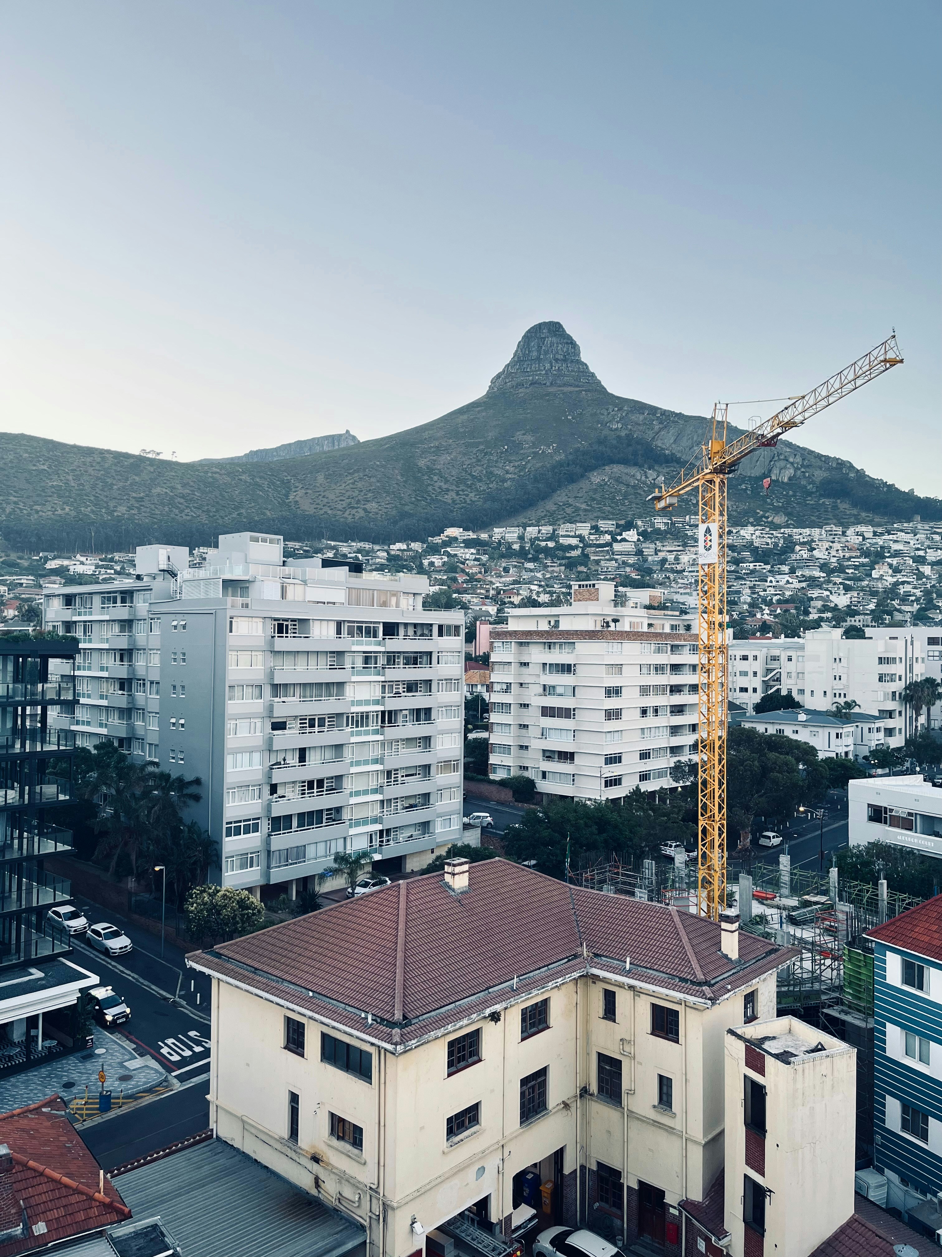 Crane Over the Hill: A Cityscape Framed by a Prominent Peak