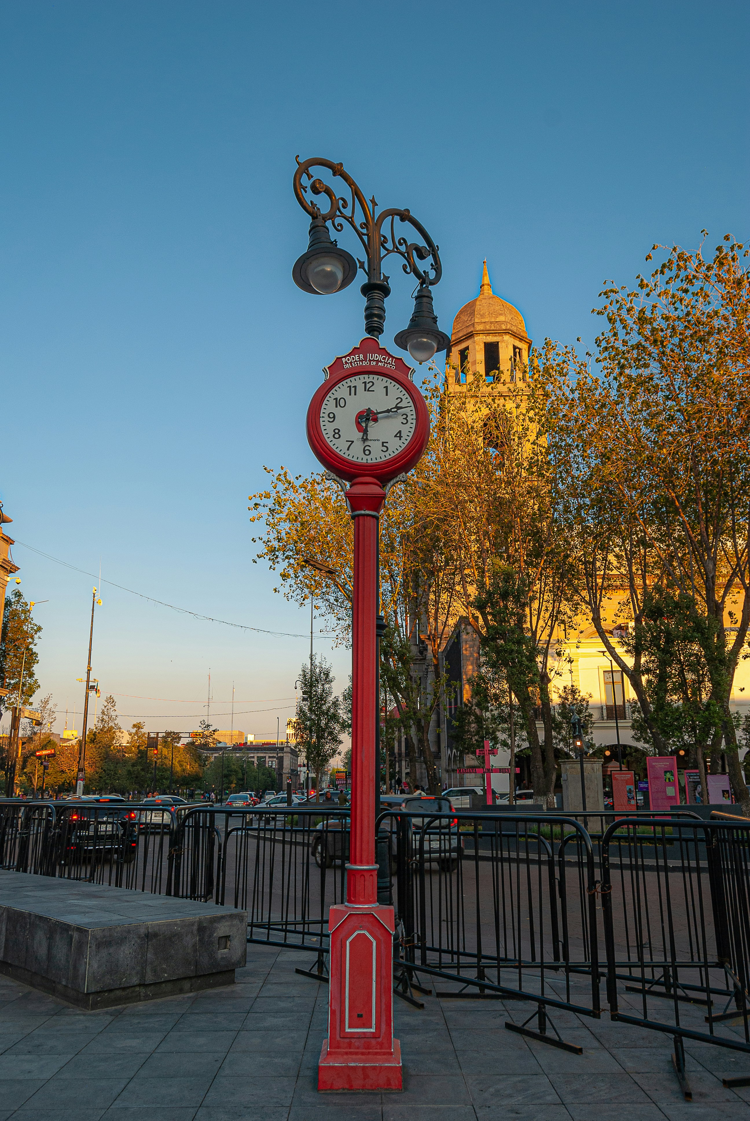 A red clock on a pole in front of a fence photo – Free City Image on ...