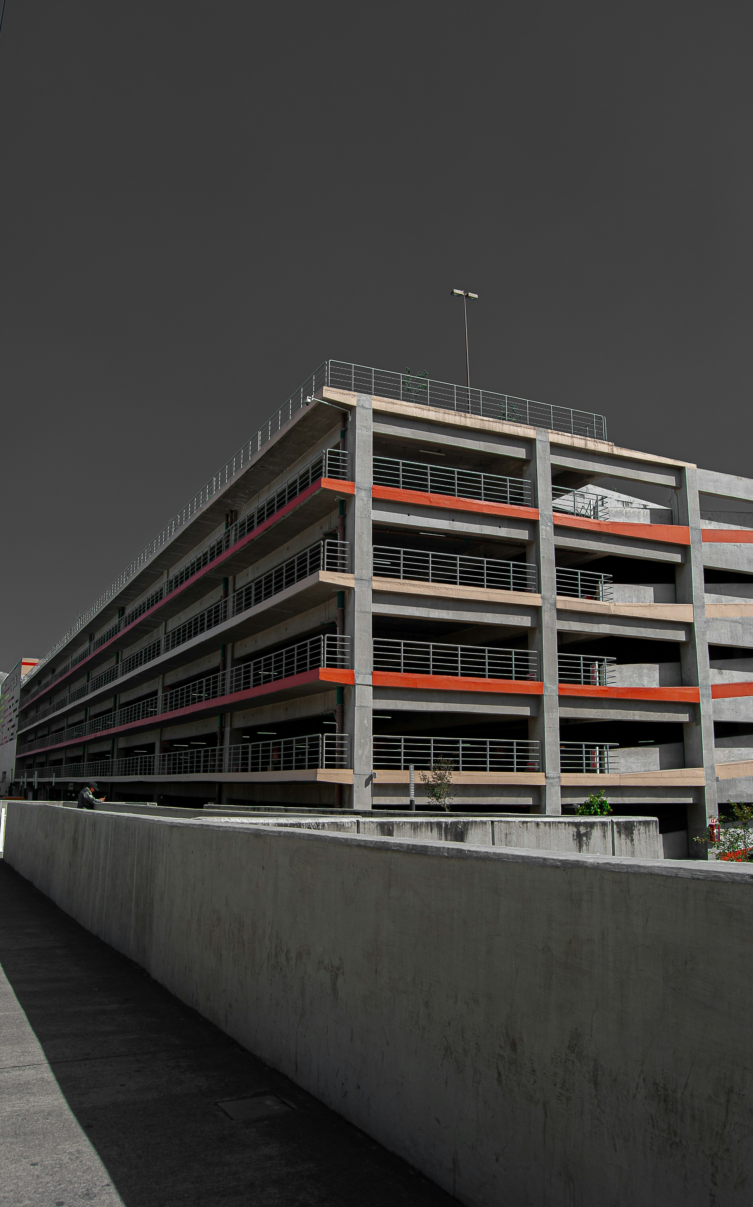 Concrete Angles: Orange Ribbons on a Parking Garage Under a Quiet Sky