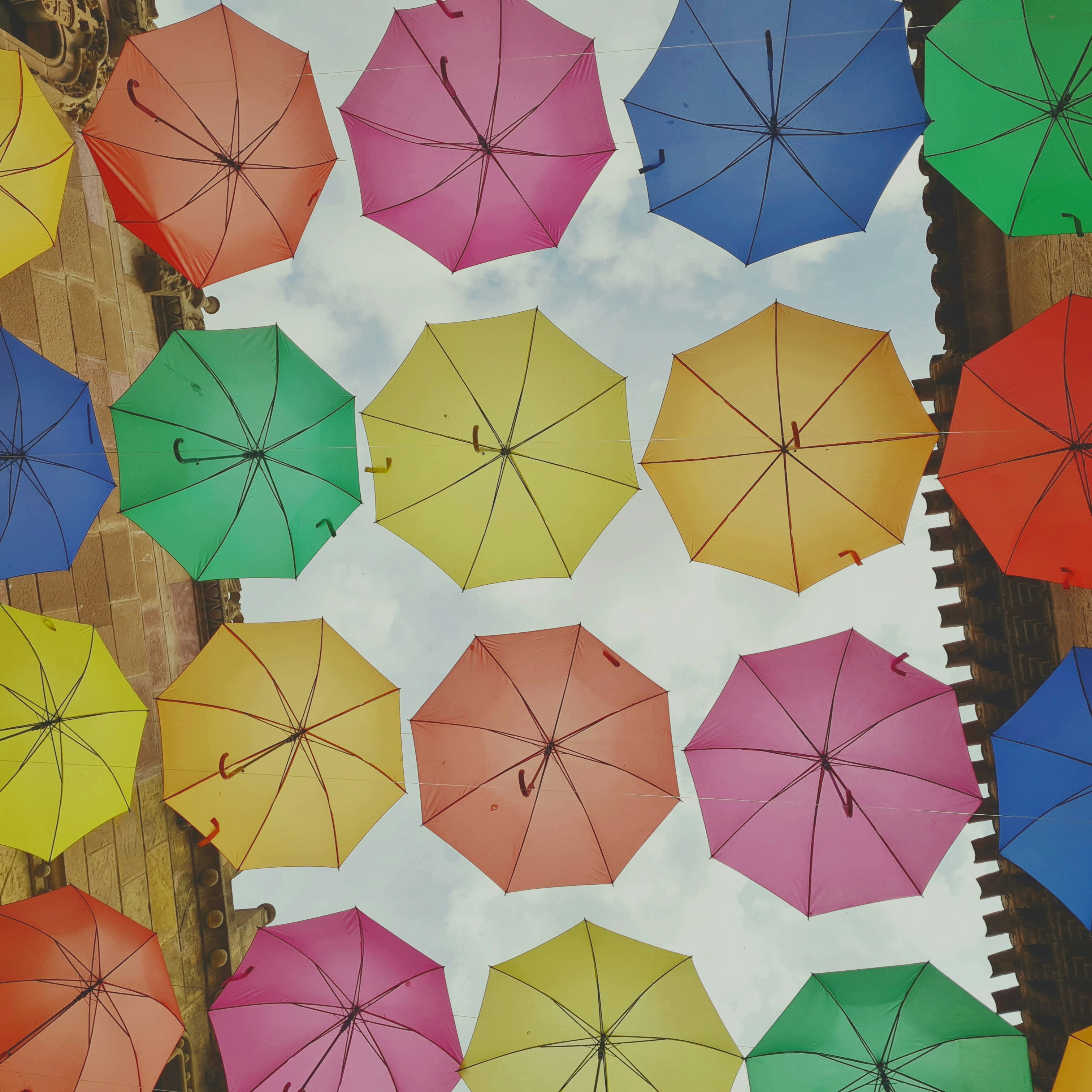 A bunch of colorful umbrellas hanging up in the air photo – Free Poble ...