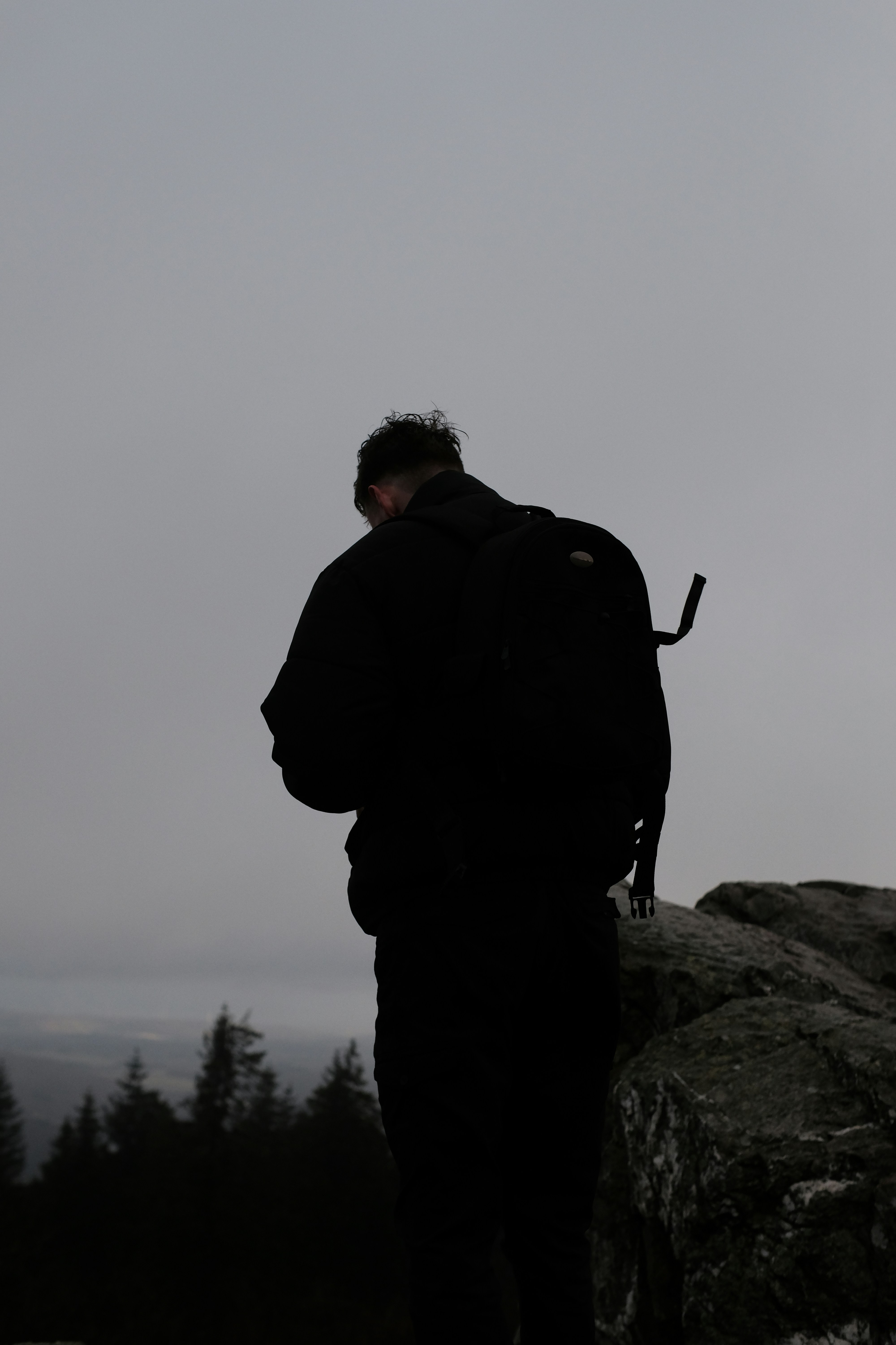 Edge of Silence: A solitary climber silhouette on a rocky escarpment under an overcast sky
