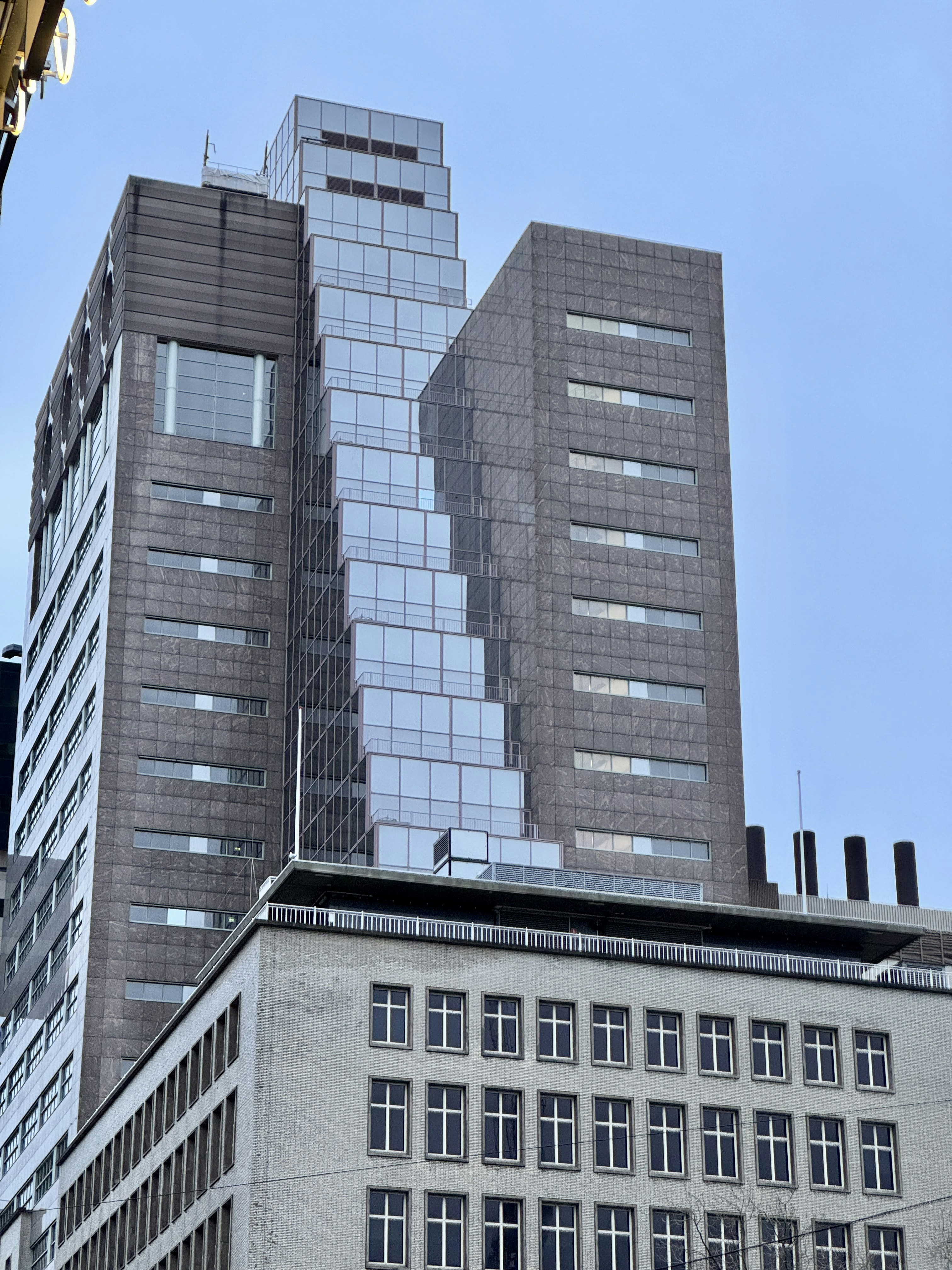 Glass Spine Between Brick Giants: A Skyward Tower in Urban Contrast