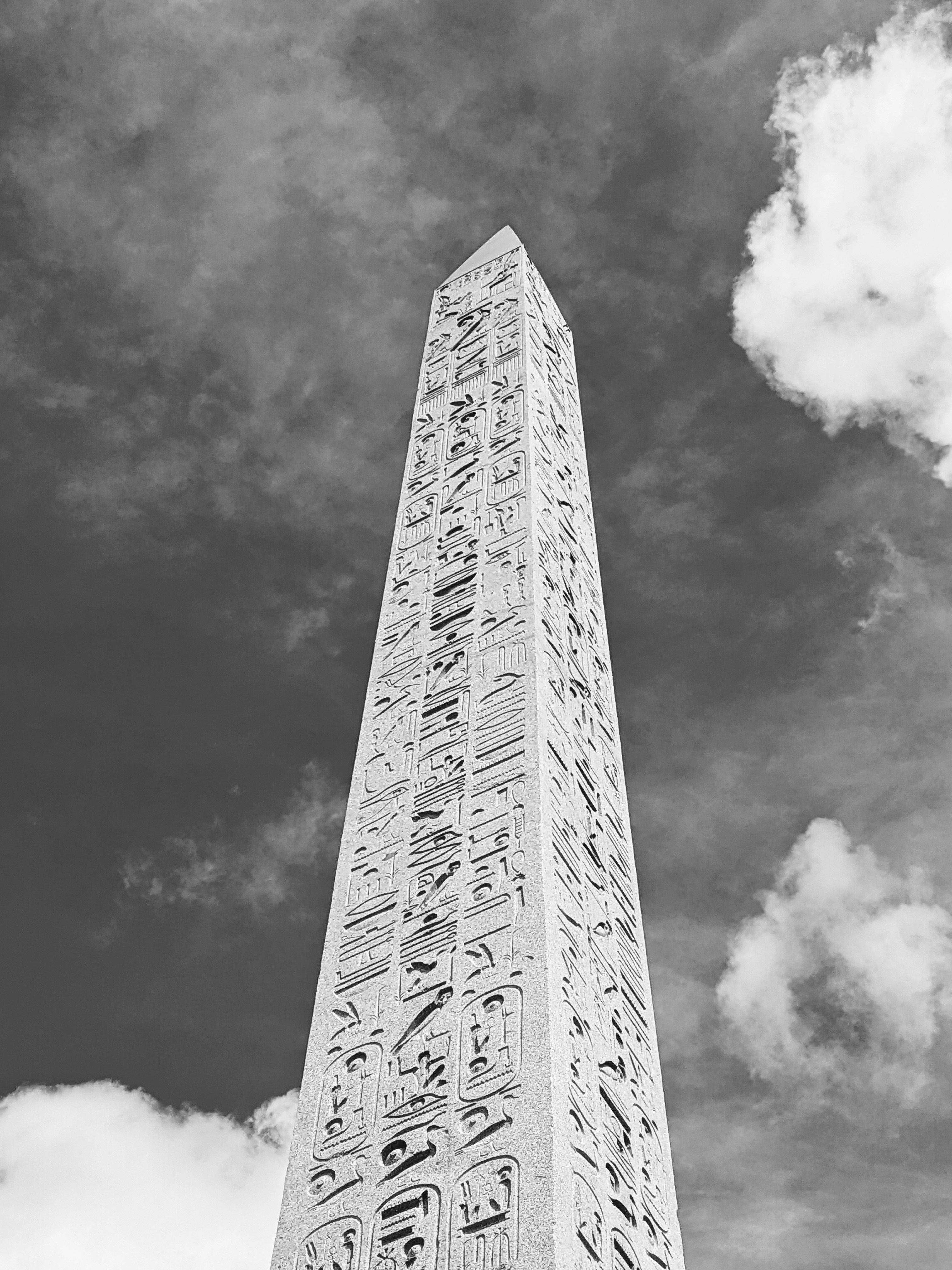 A tall obelisk with writing on it against a cloudy sky photo – Free ...