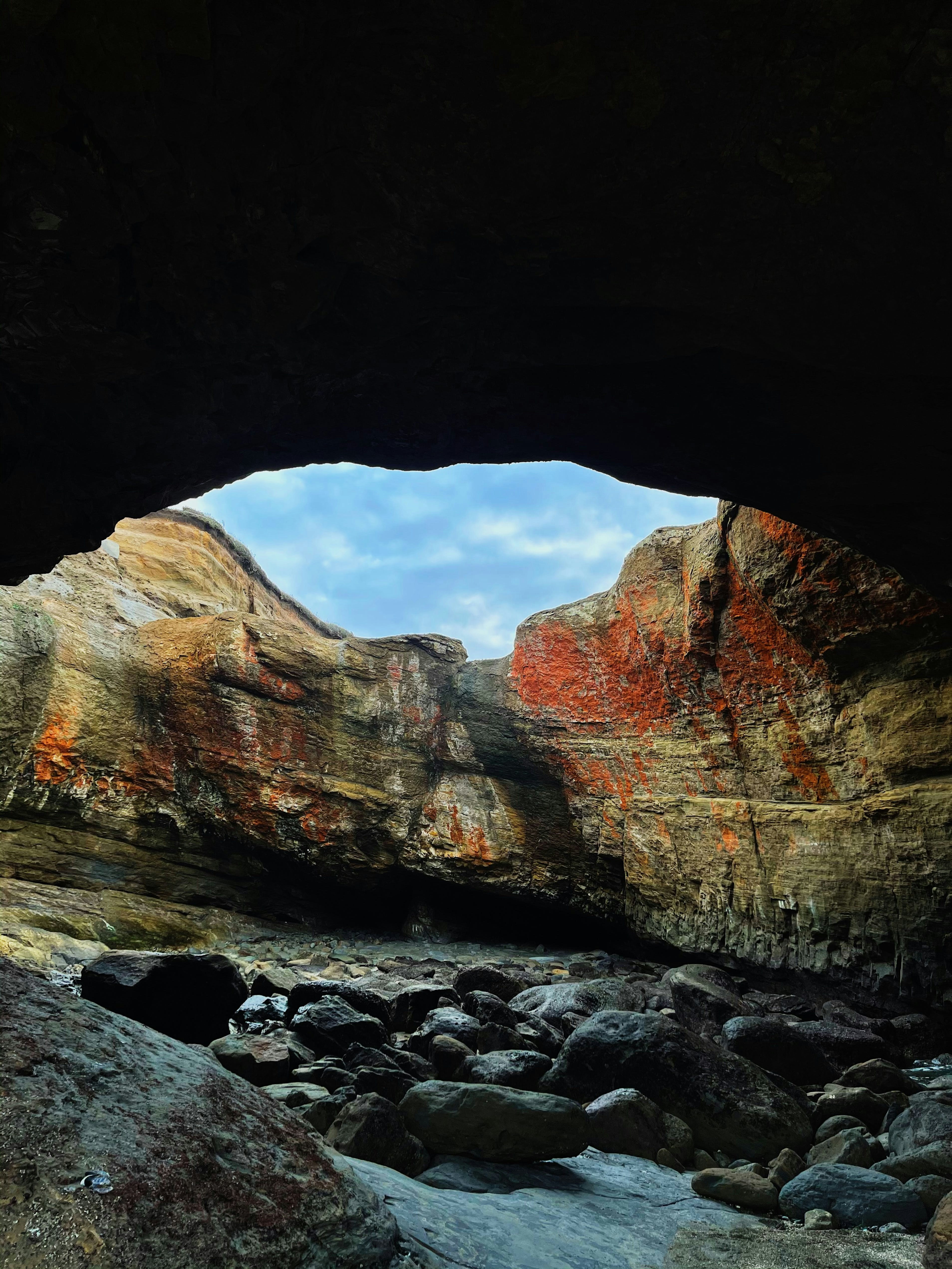 A cave with rocks and water underneath it photo – Free Cave Image on ...