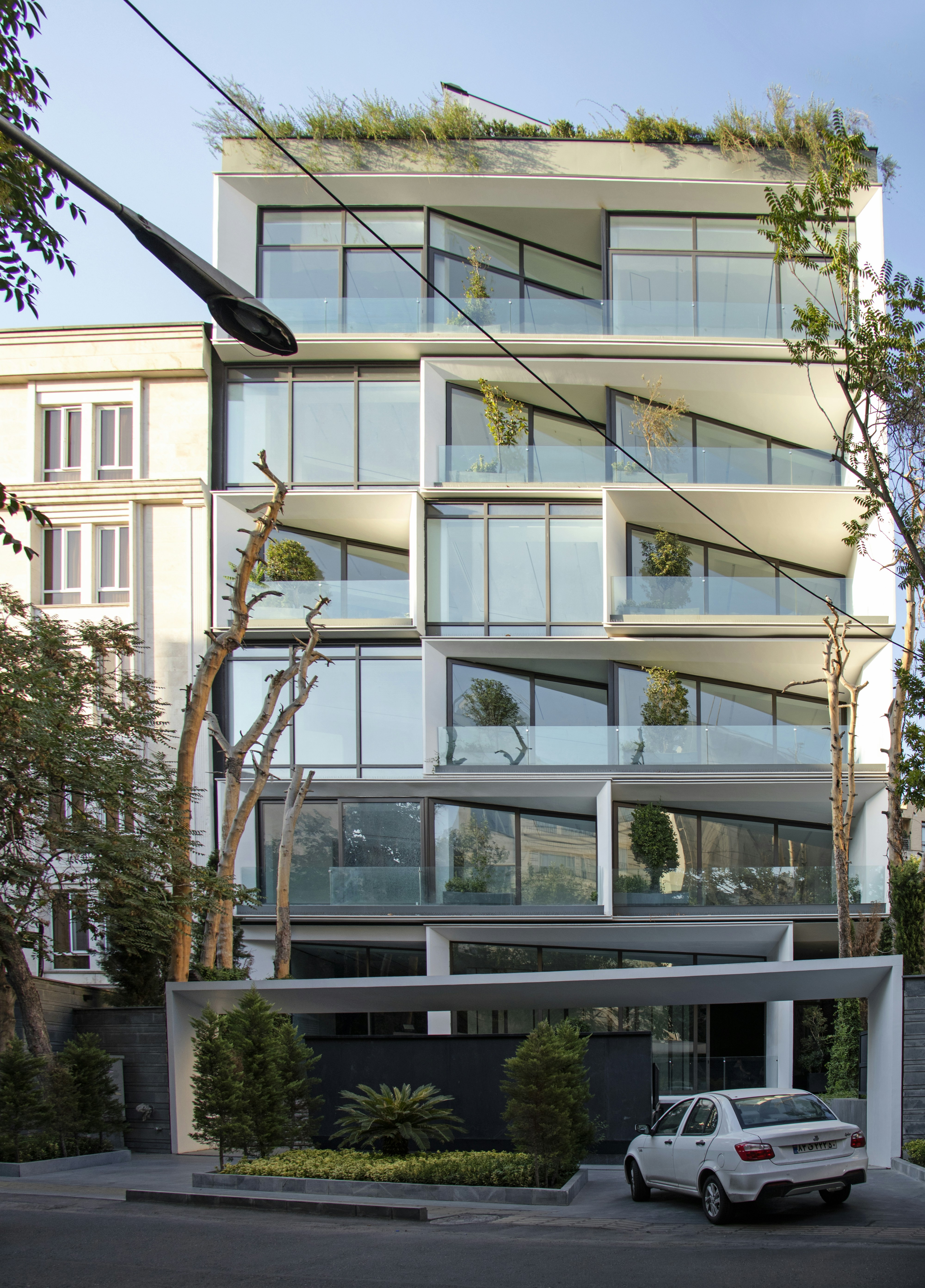 Contemporary building featuring dynamic glass facades and integrated greenery, showcasing innovative architectural design. The structure blends seamlessly with its urban environment.