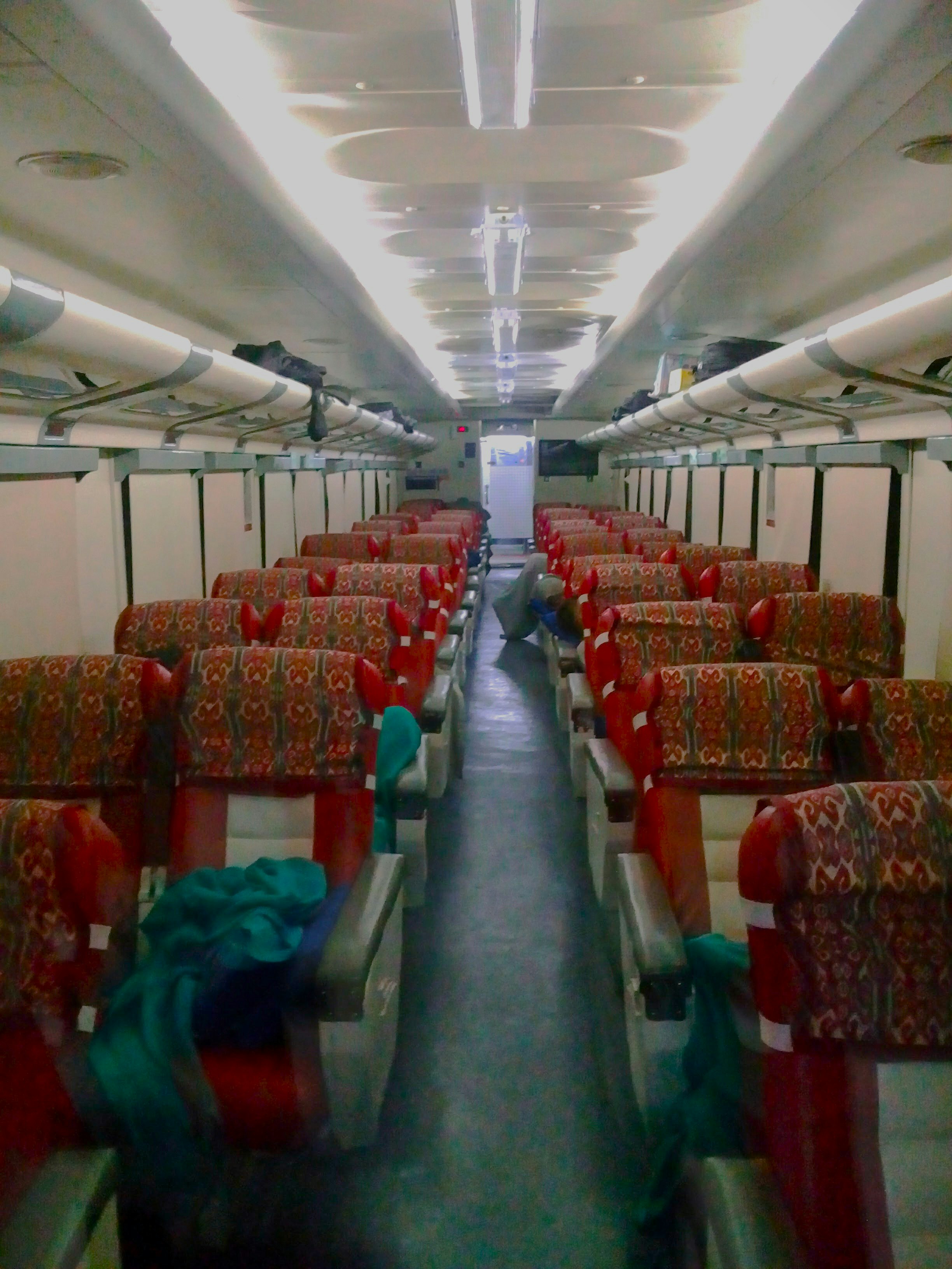 An empty train car with red seats and colorful blankets photo – Free ...
