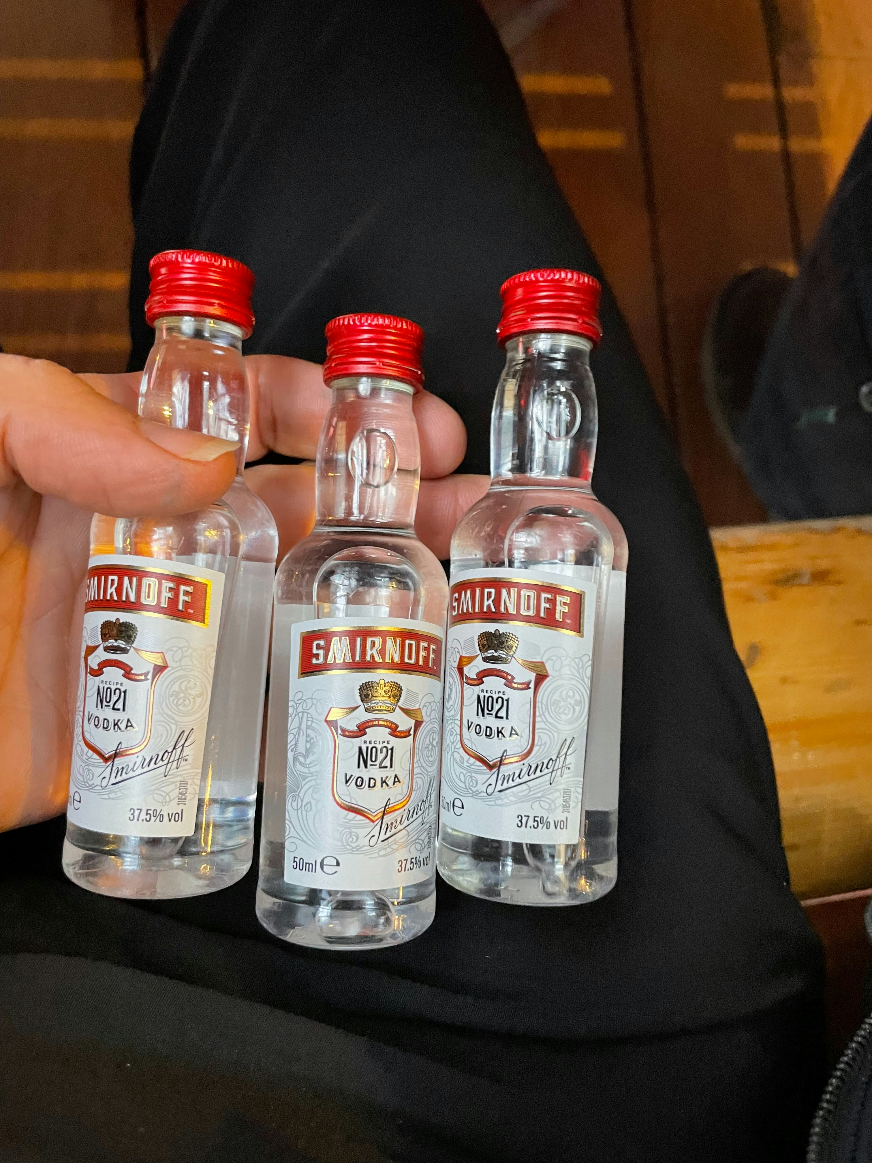 A person holding three bottles of vodka in their hands photo – Free ...