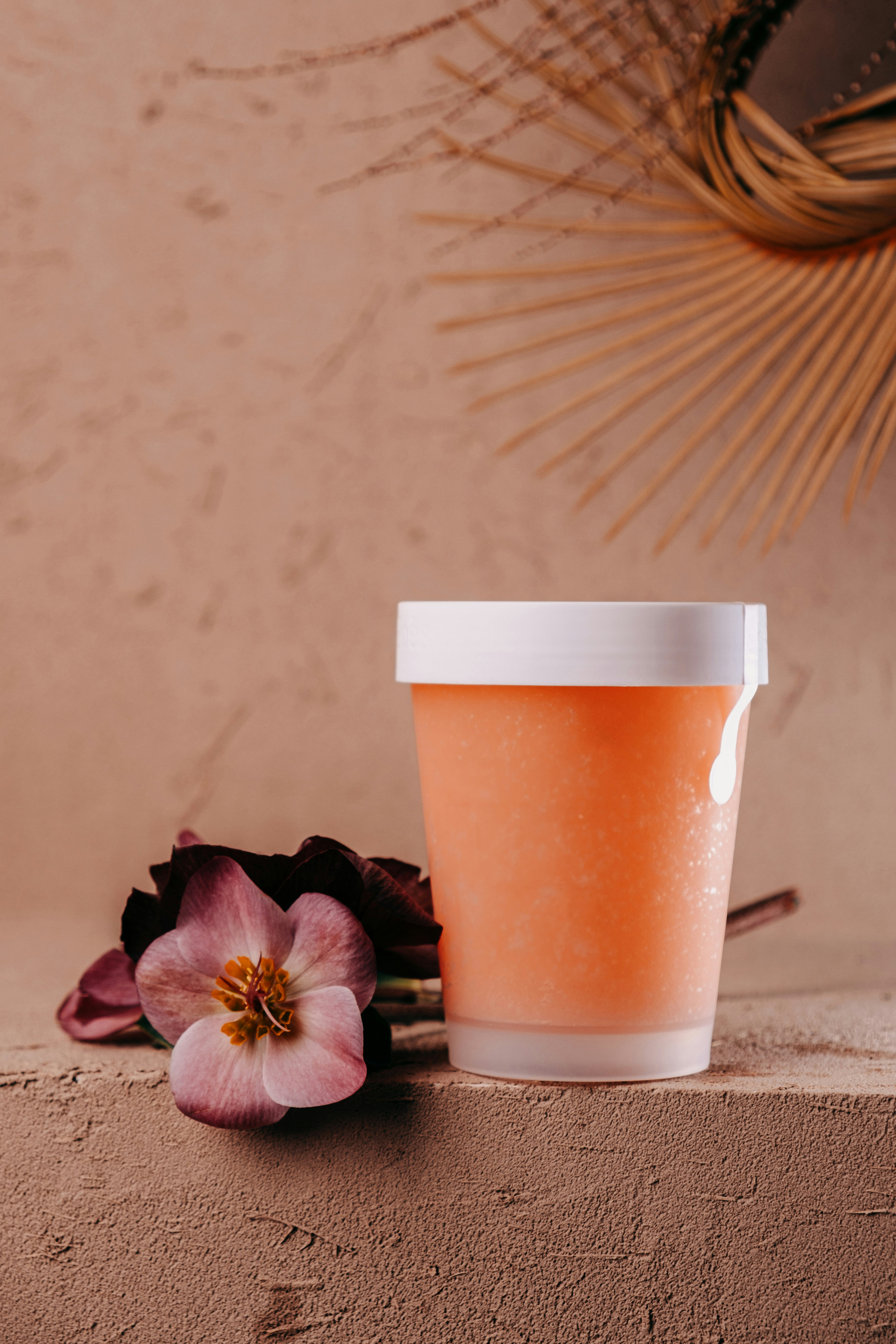 Peach Smoothie in a Minimal Studio, Framed by Orchid and Palm