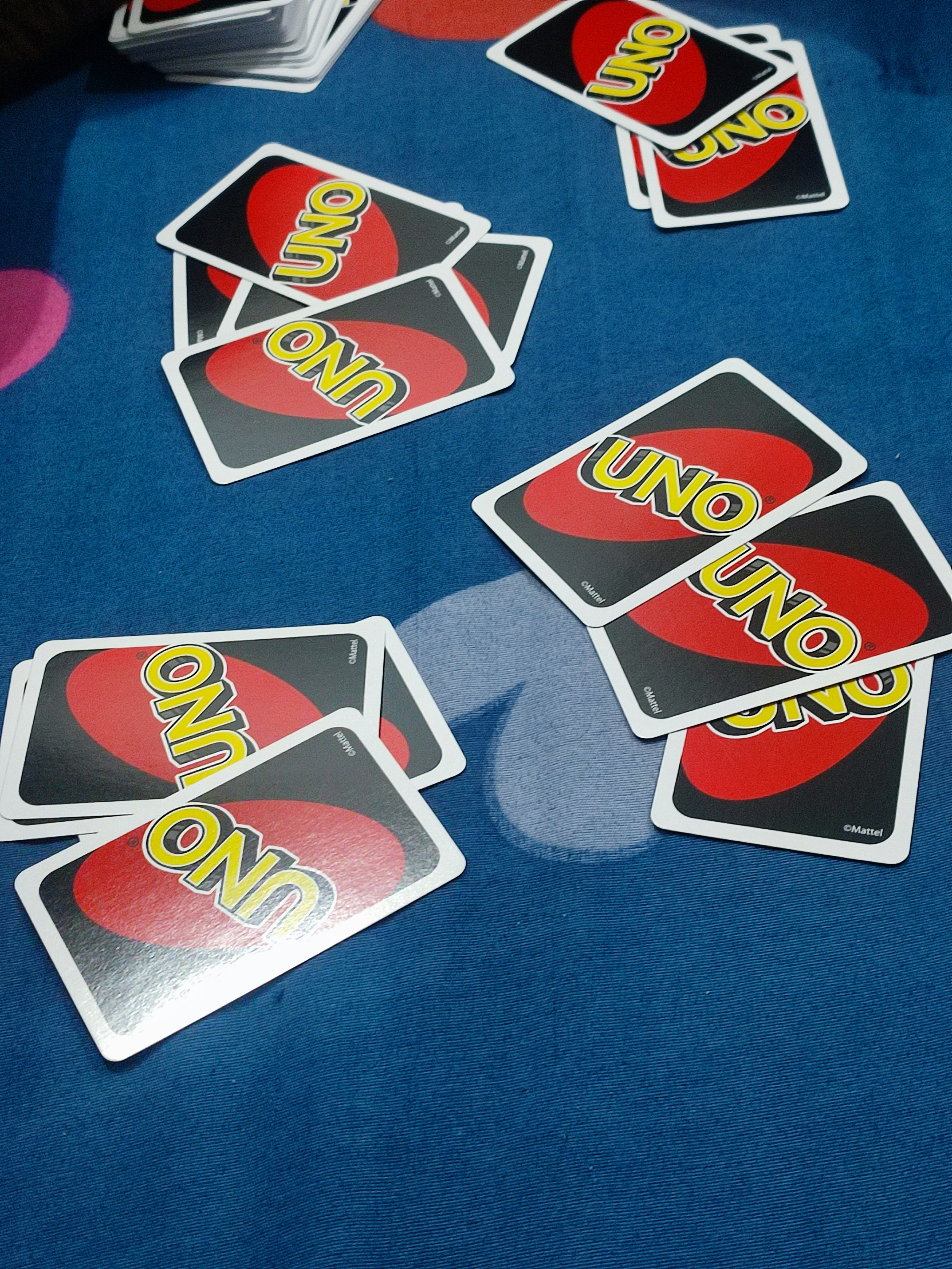 Scattered UNO cards on a vibrant blue tablecloth, showcasing the game's playful spirit.