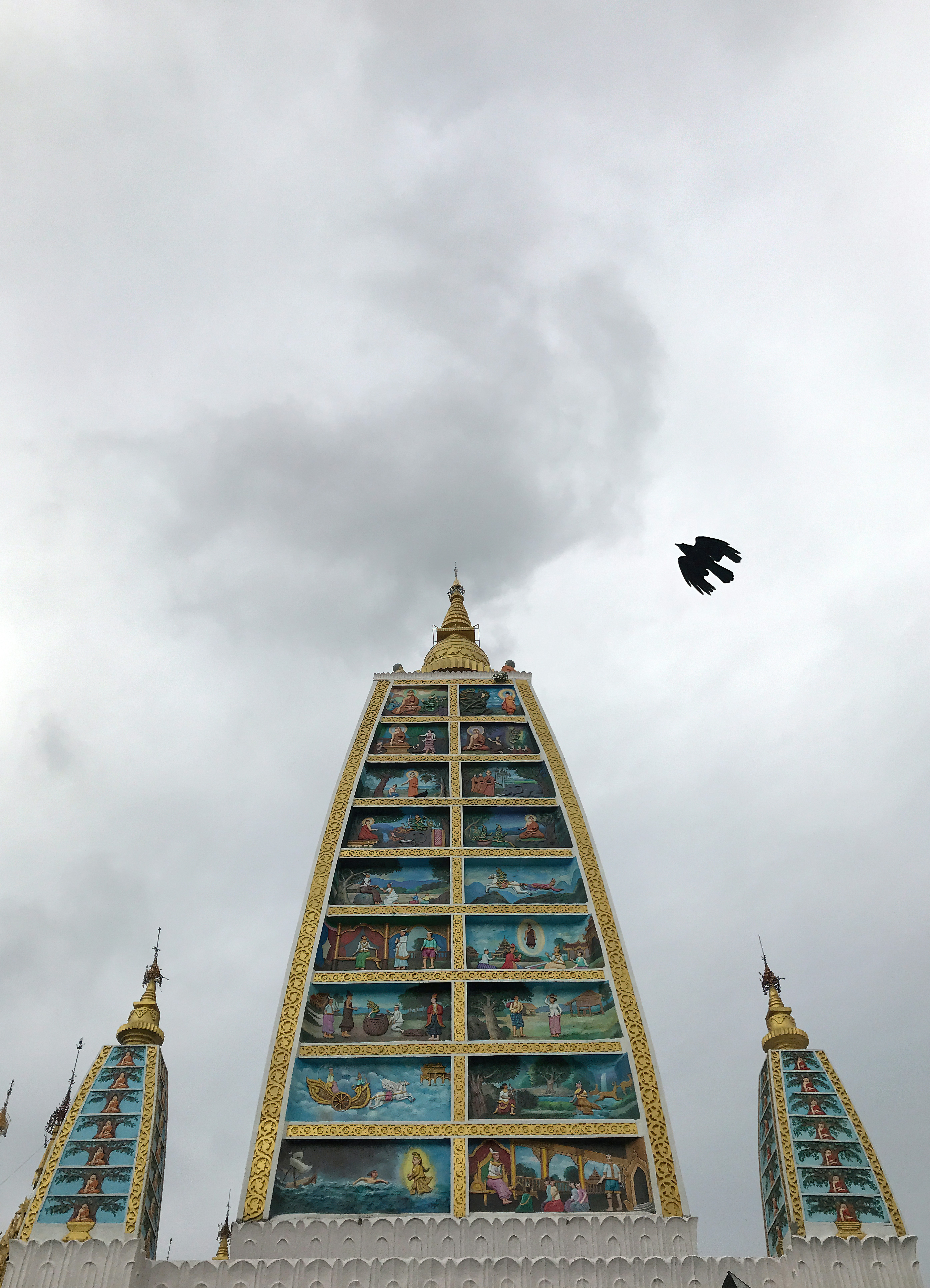 Tiered Gopuram Murals under a Moody Sky, with a Bird in Flight