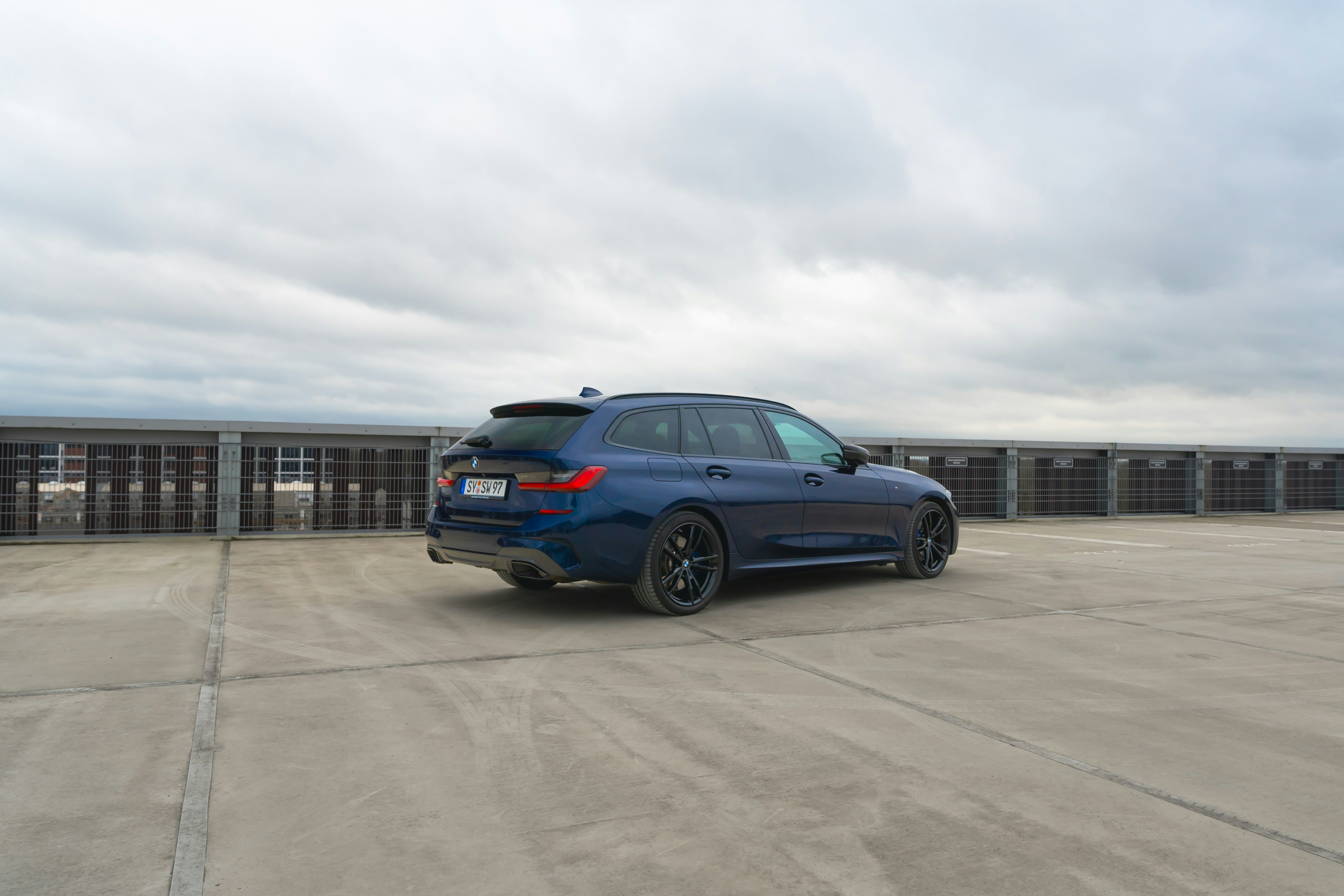 Blue sedan parked on an expansive rooftop with overcast skies.