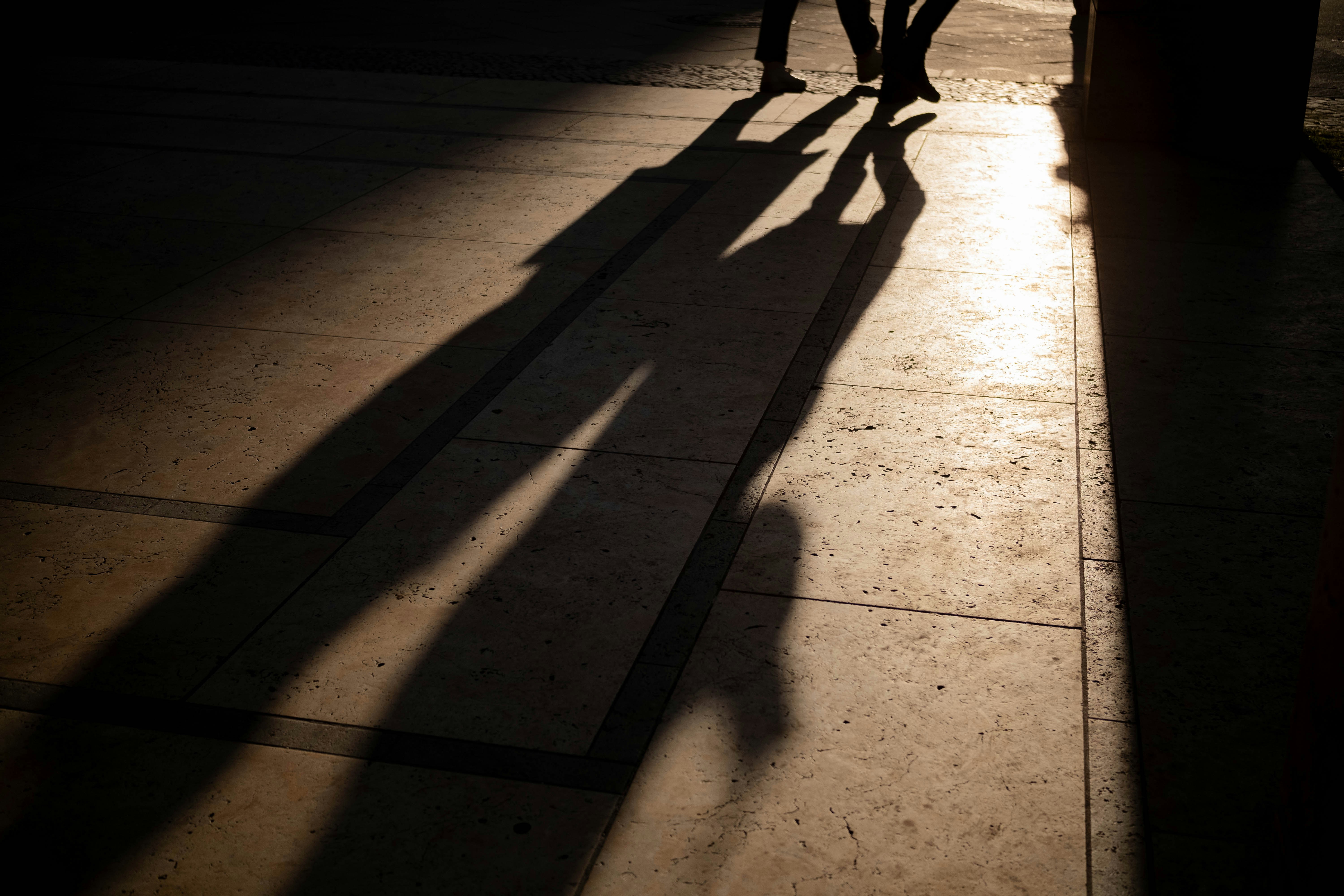 A shadow of two people standing on a sidewalk photo – Free Urban Image ...