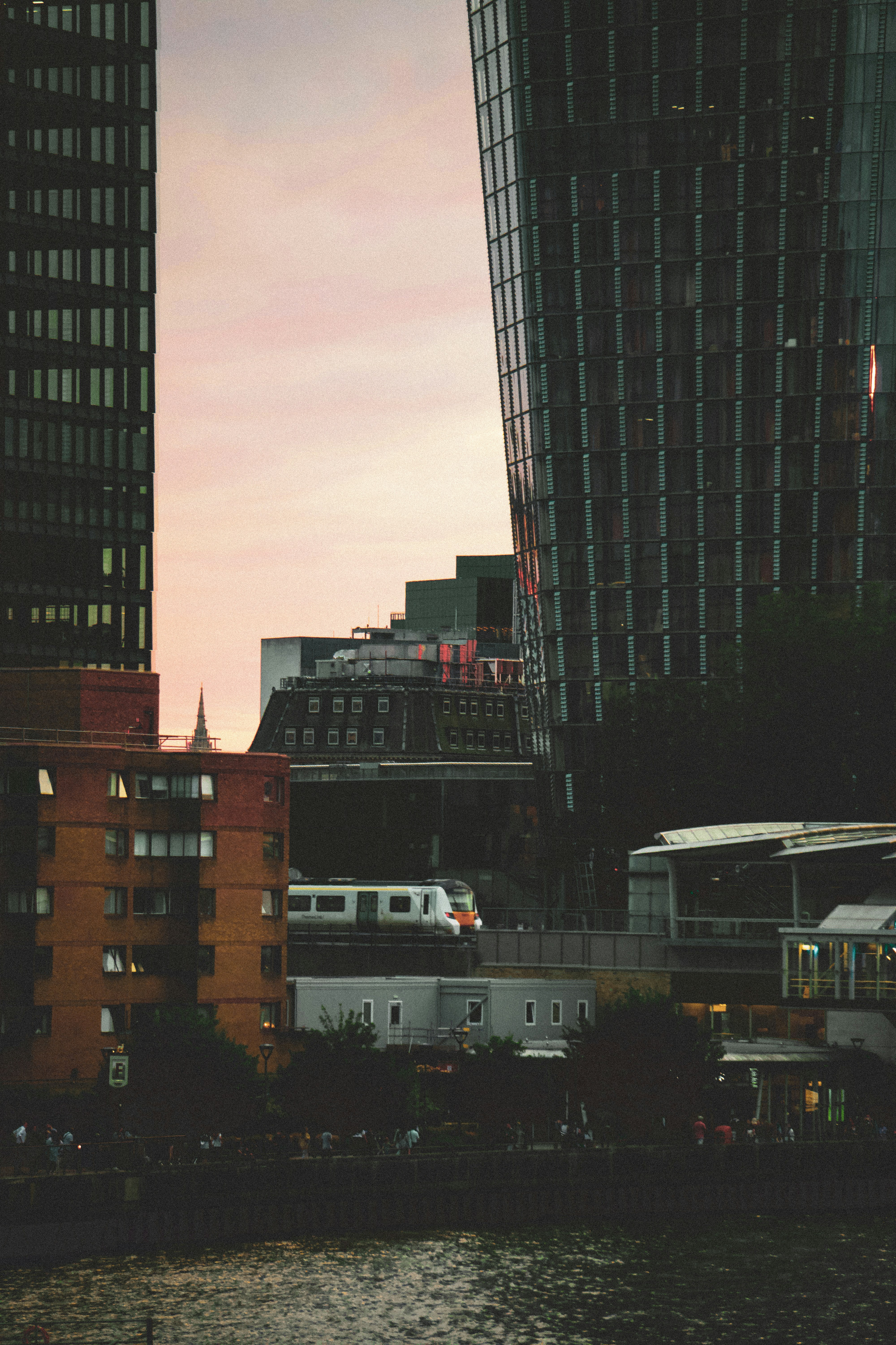 Dusk Between Glass Giants: Riverside Transit at Sunset