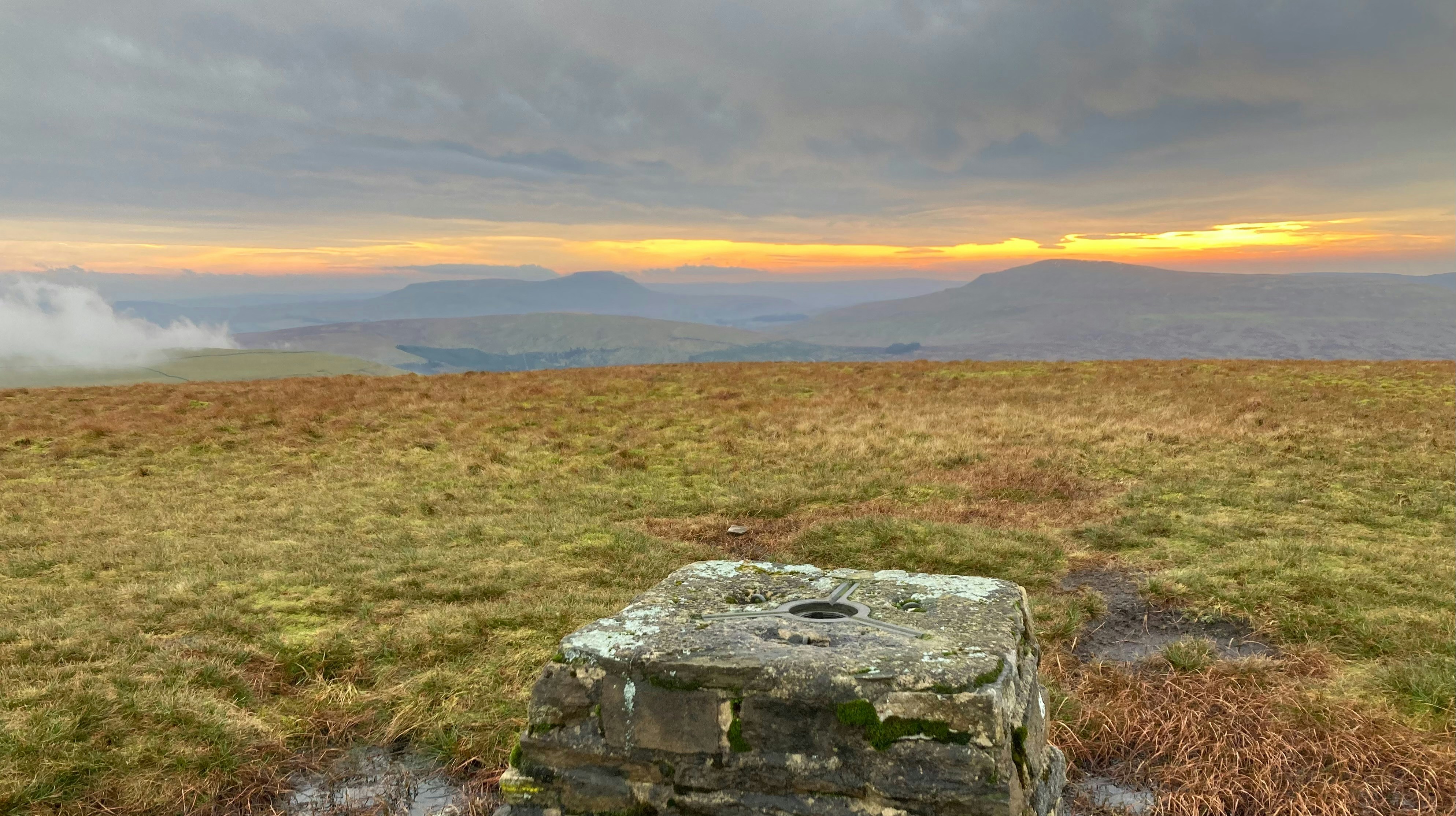 A stone bench sitting on top of a grass covered field photo – Free ...