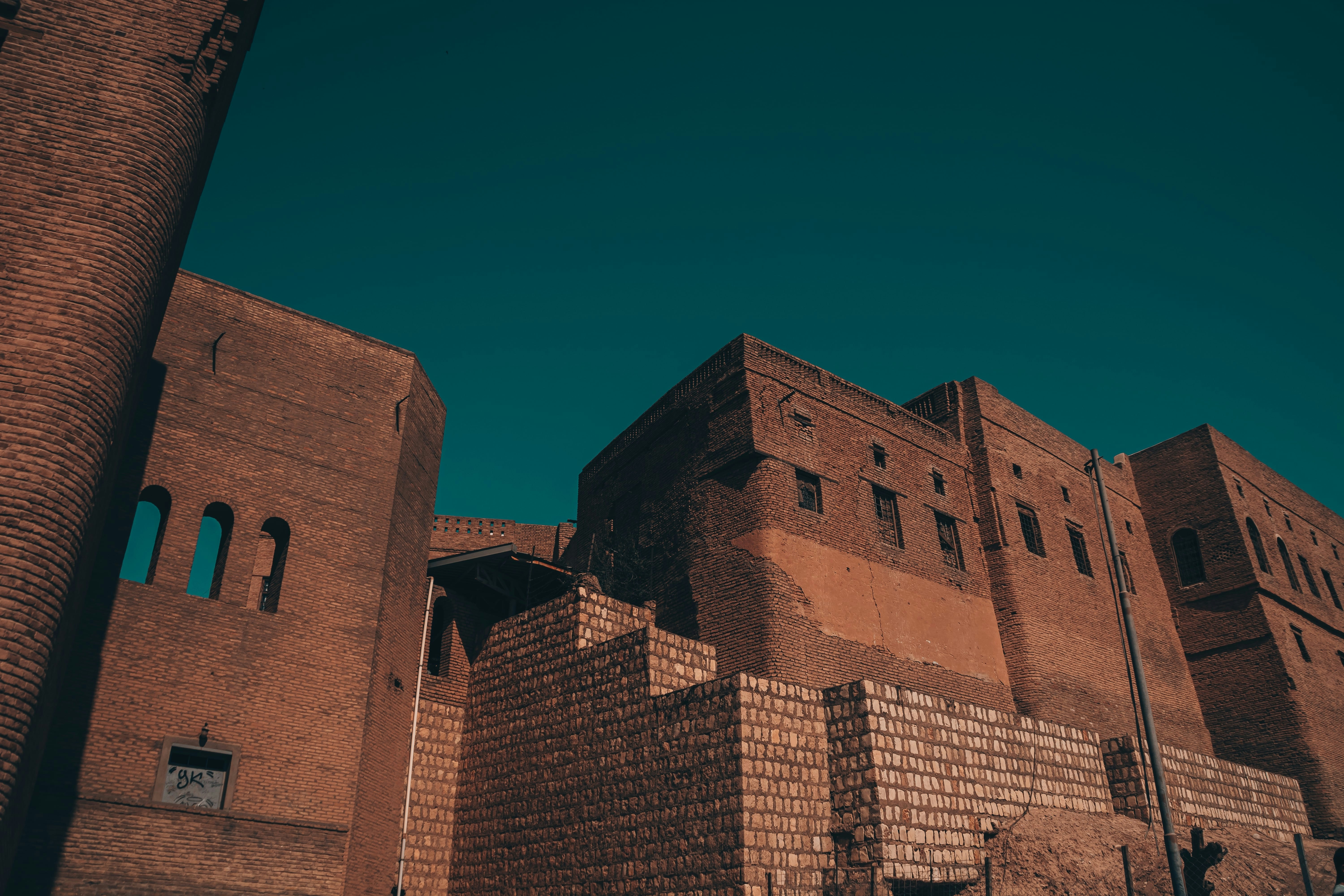A tall brick building with a clock on it's side photo – Free Erbil ...