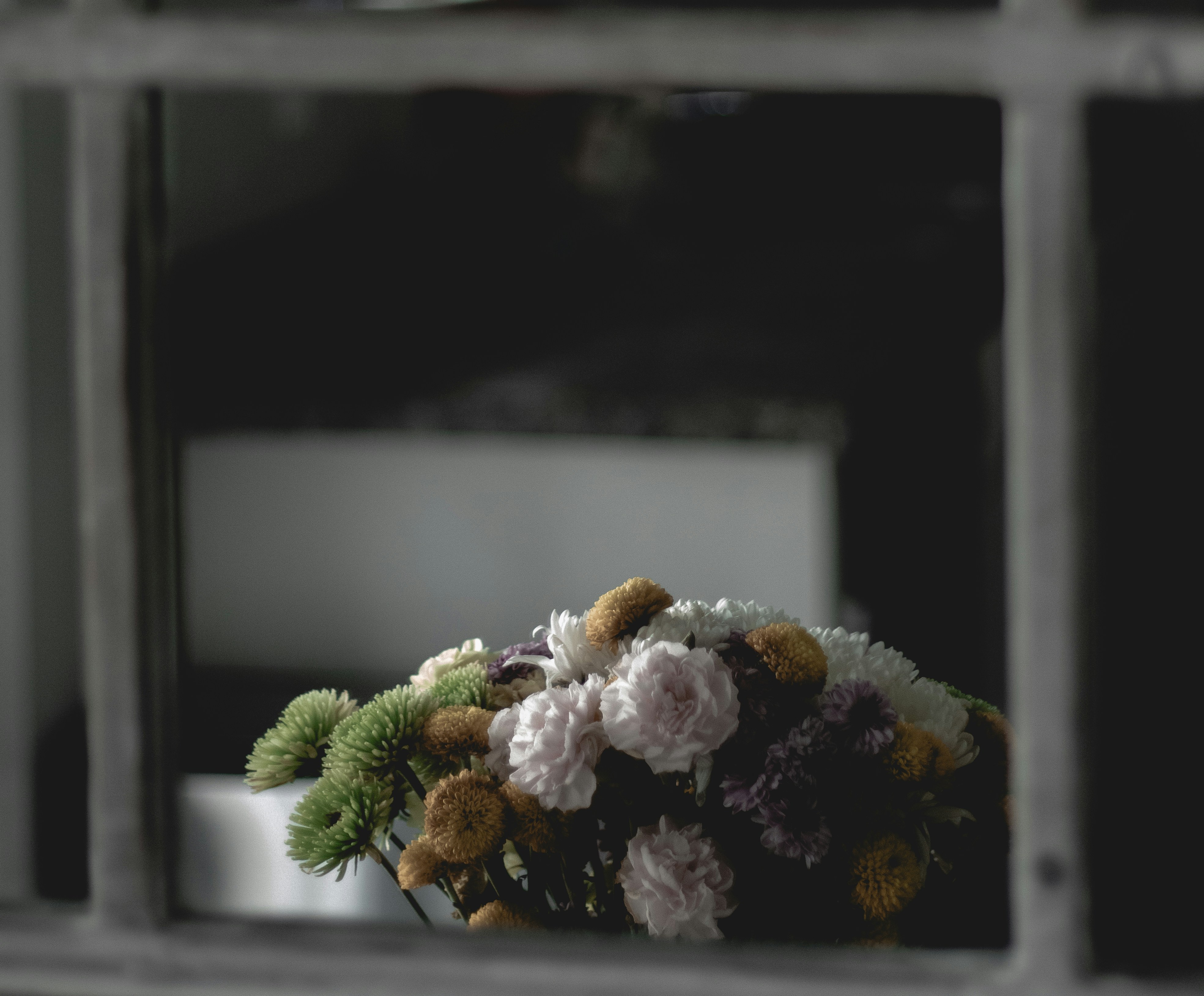 Framed Quiet Bloom: a bouquet behind a weathered window grid