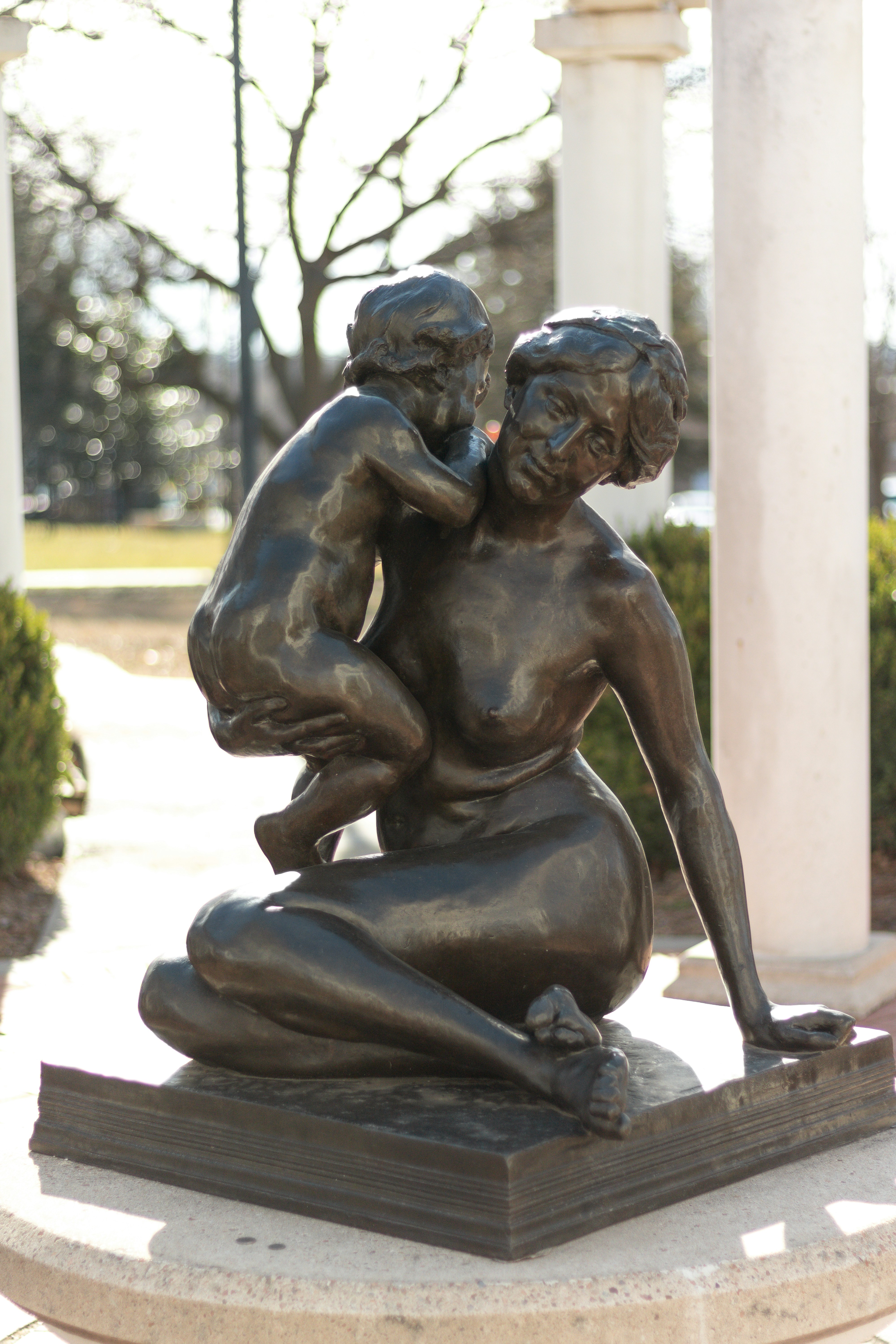 Sunlit Bronze Embrace: A Mother and Child in Quiet Park