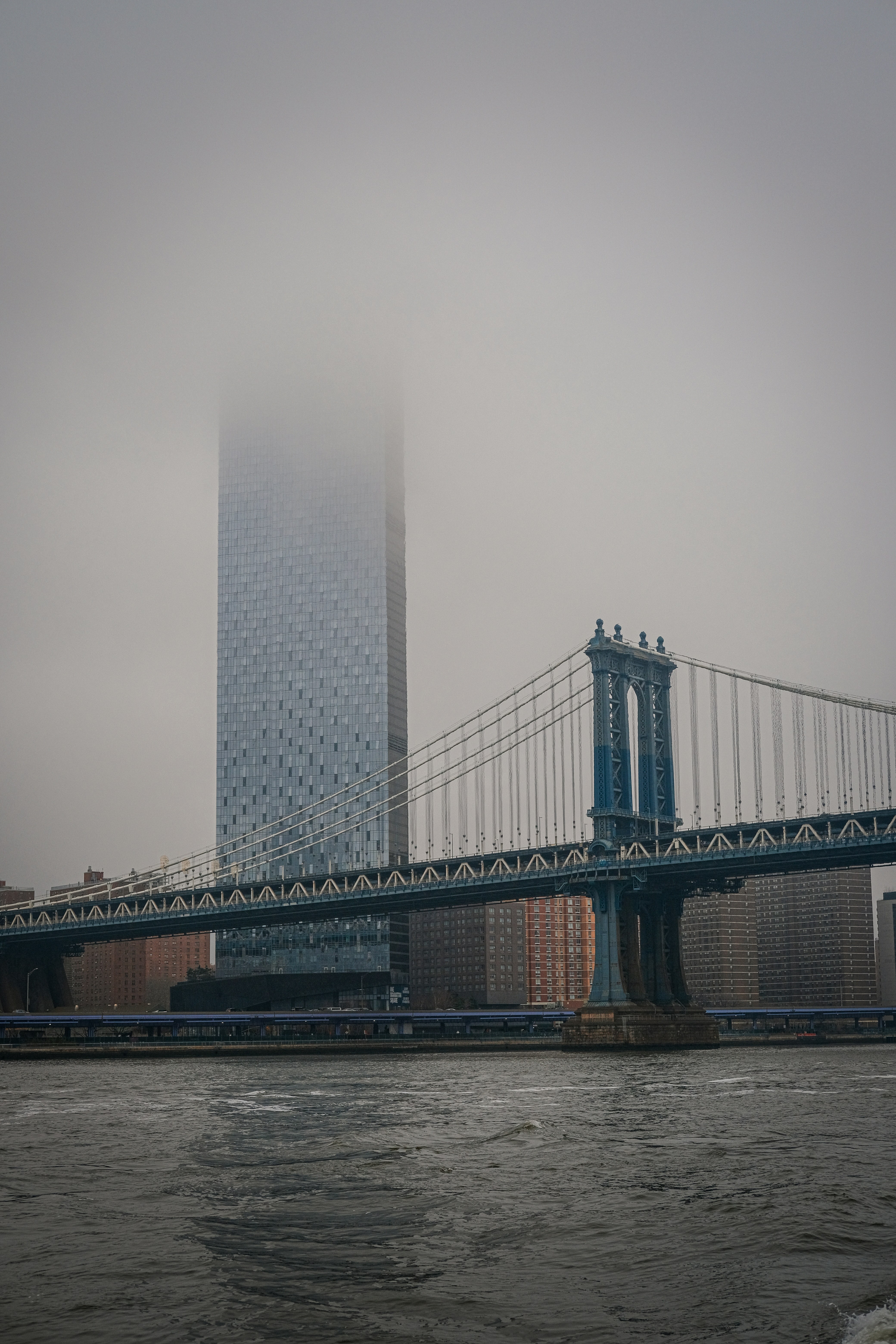 Fog-Laced Suspension: A Cobalt Bridge Against a Veiled Glass Skyscraper