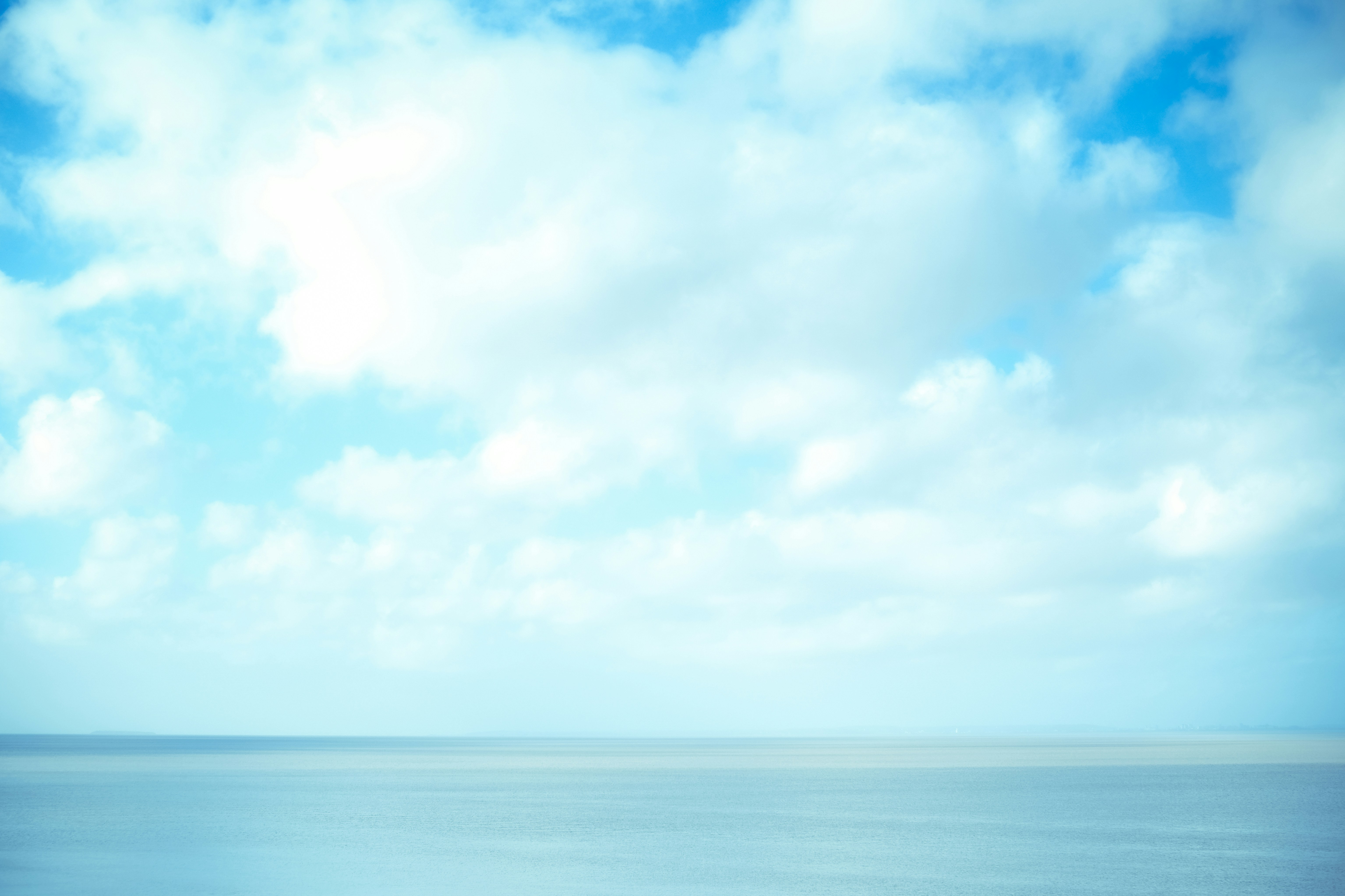 a large body of water sitting under a cloudy blue sky