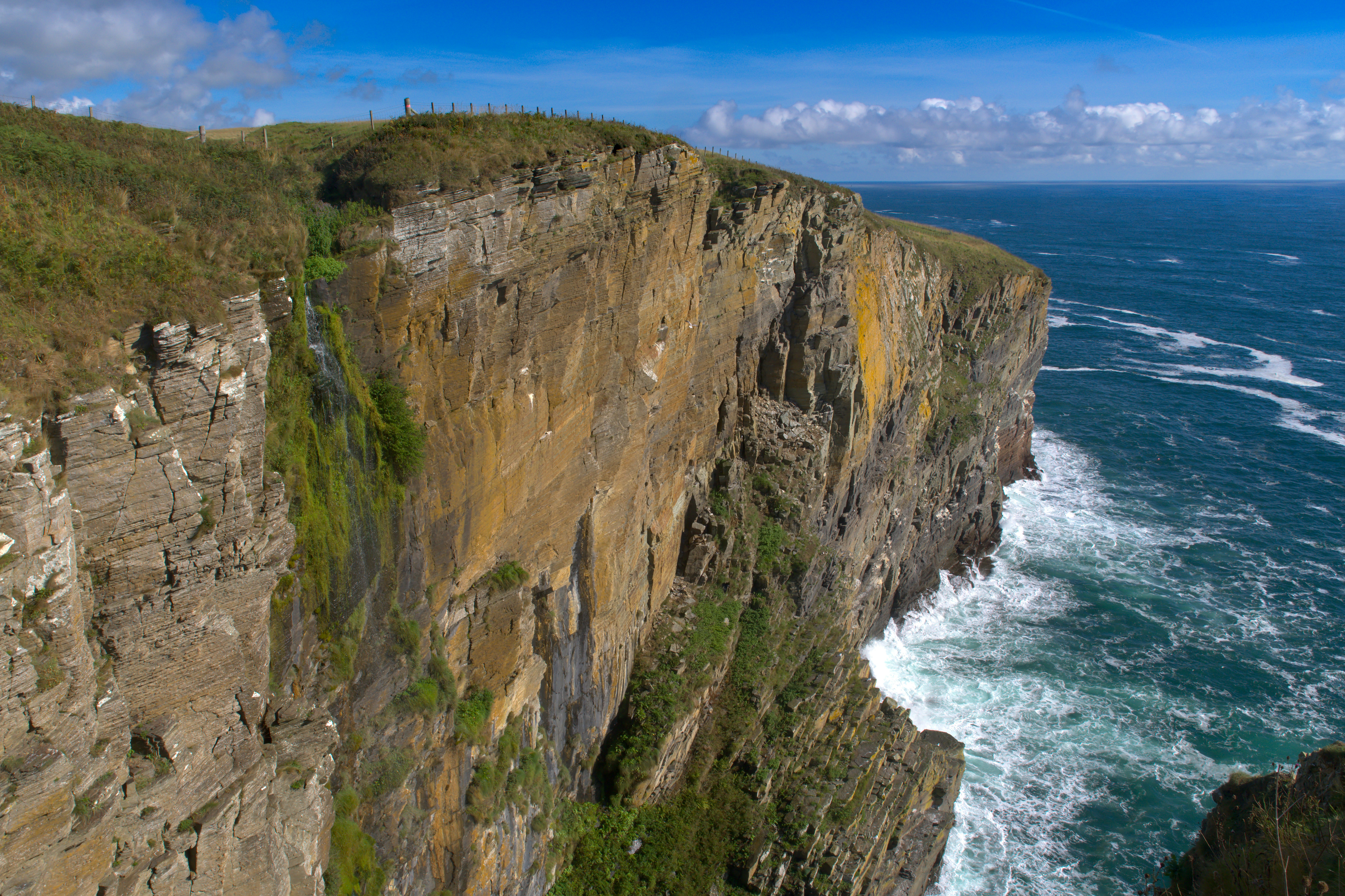 A large cliff with a cliff face next to the ocean photo – Free Cliff ...