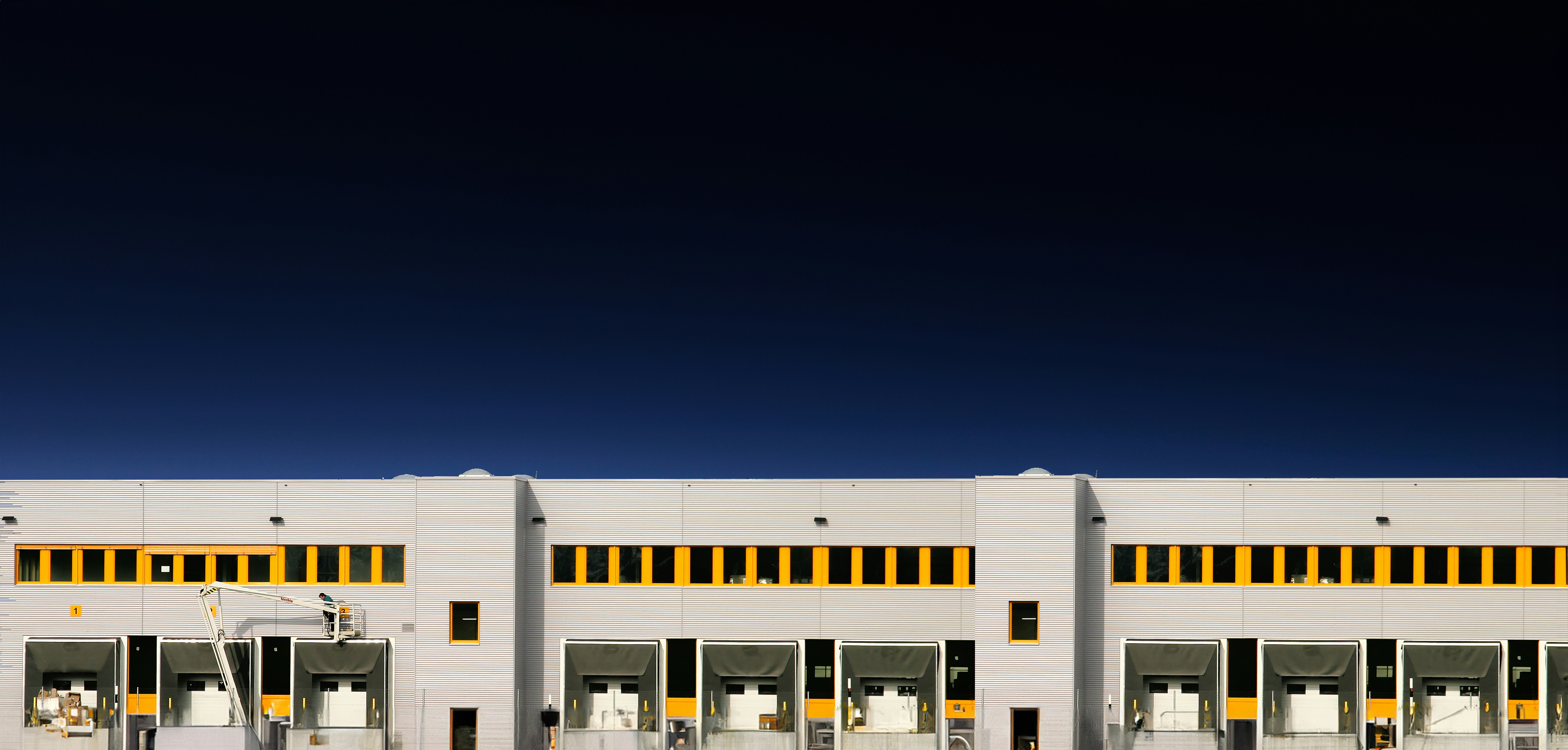 Warehouse facade with yellow accents under a deep blue twilight sky.