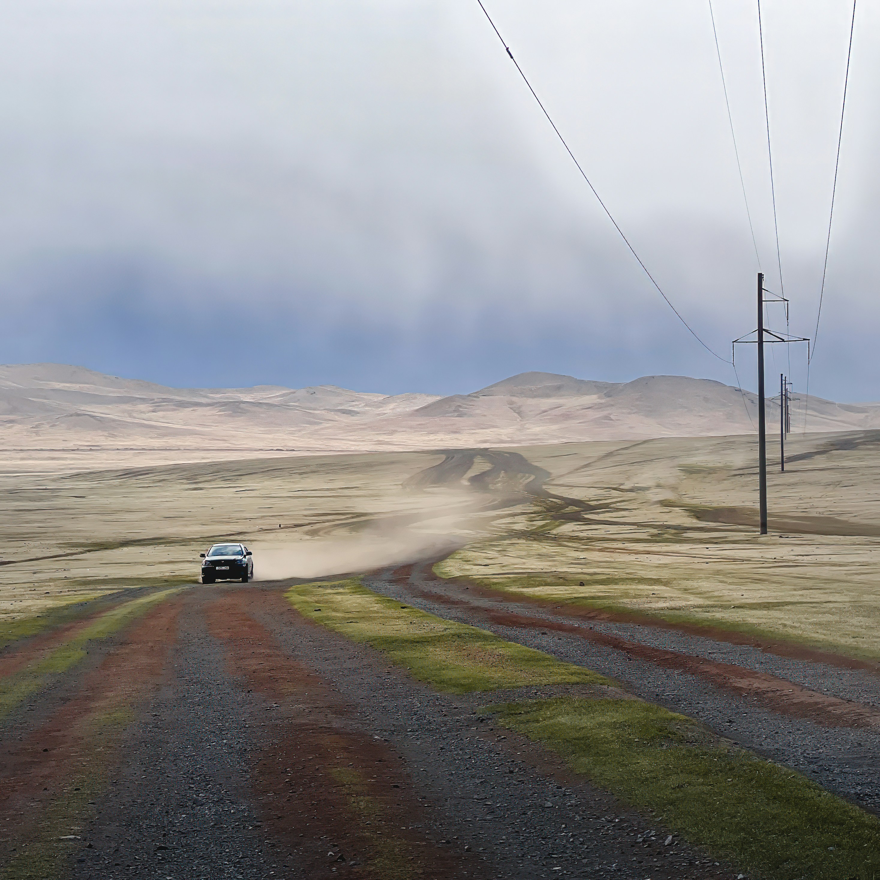 Dust Trail Horizon: A Lone Car on a Rutted Desert Road