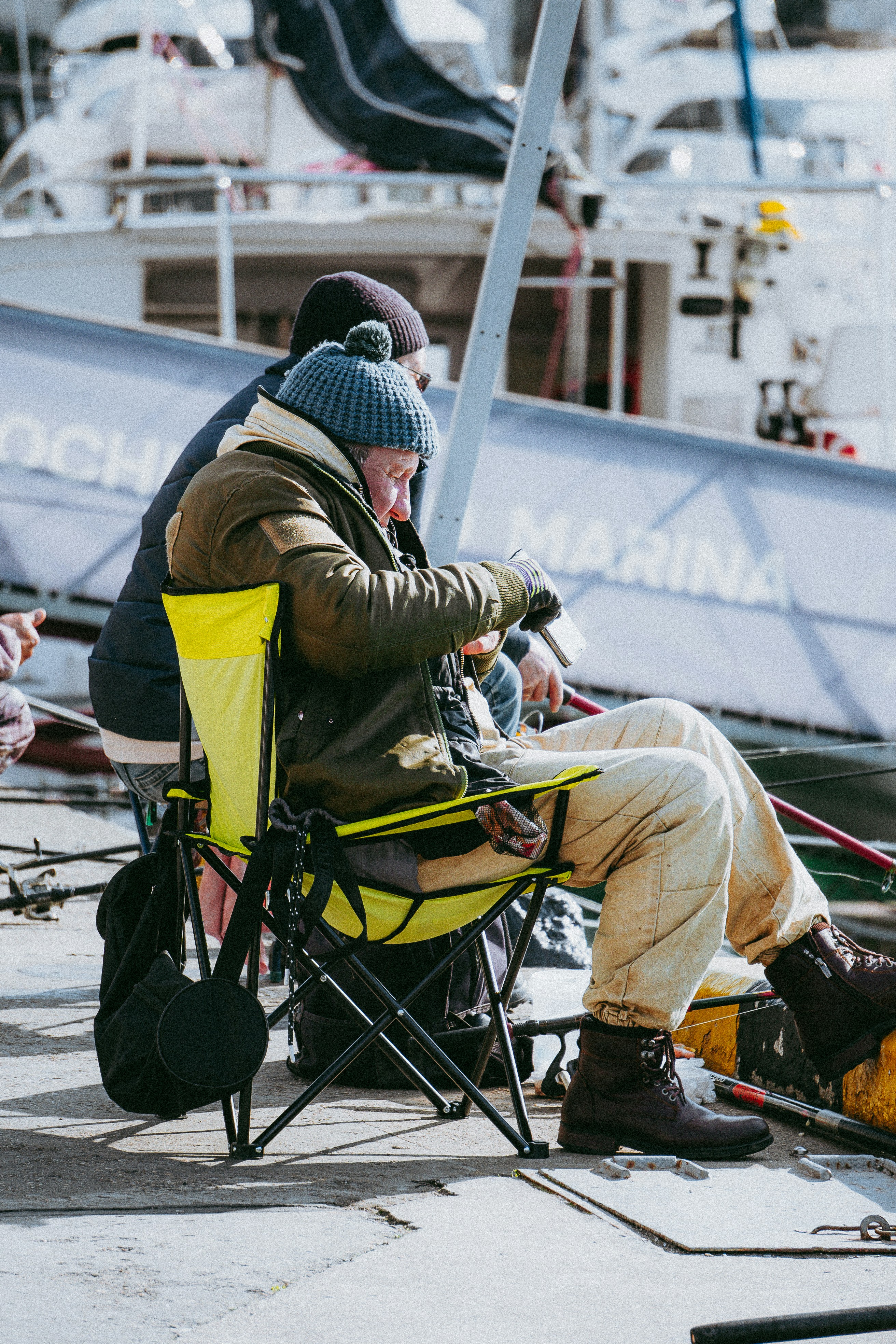 Cozy Marina Break: Elderly Angler in a Sunlit Harbor Chair
