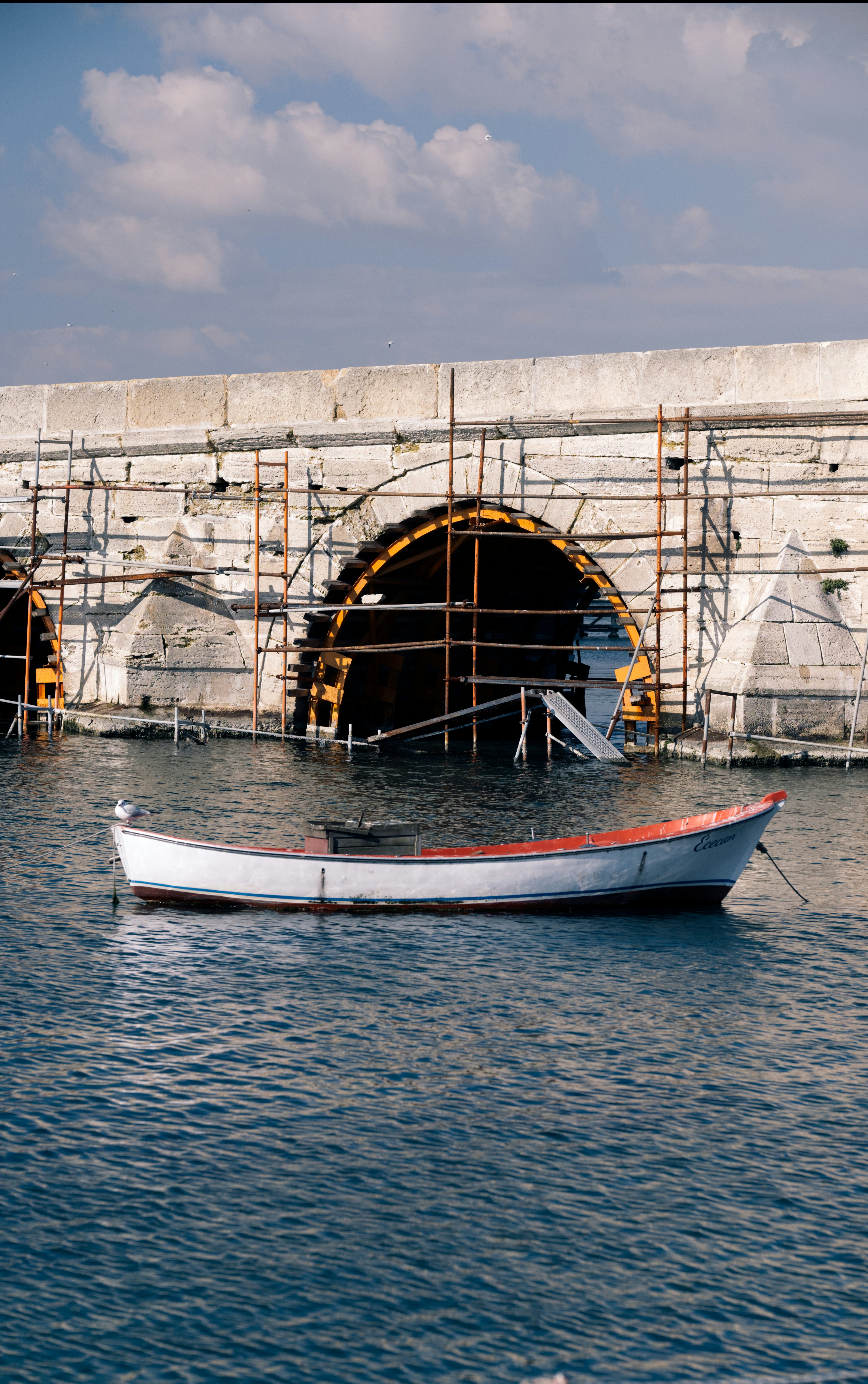 Harbor Gate: The White Rowboat Before a Scaffolded Tunnel
