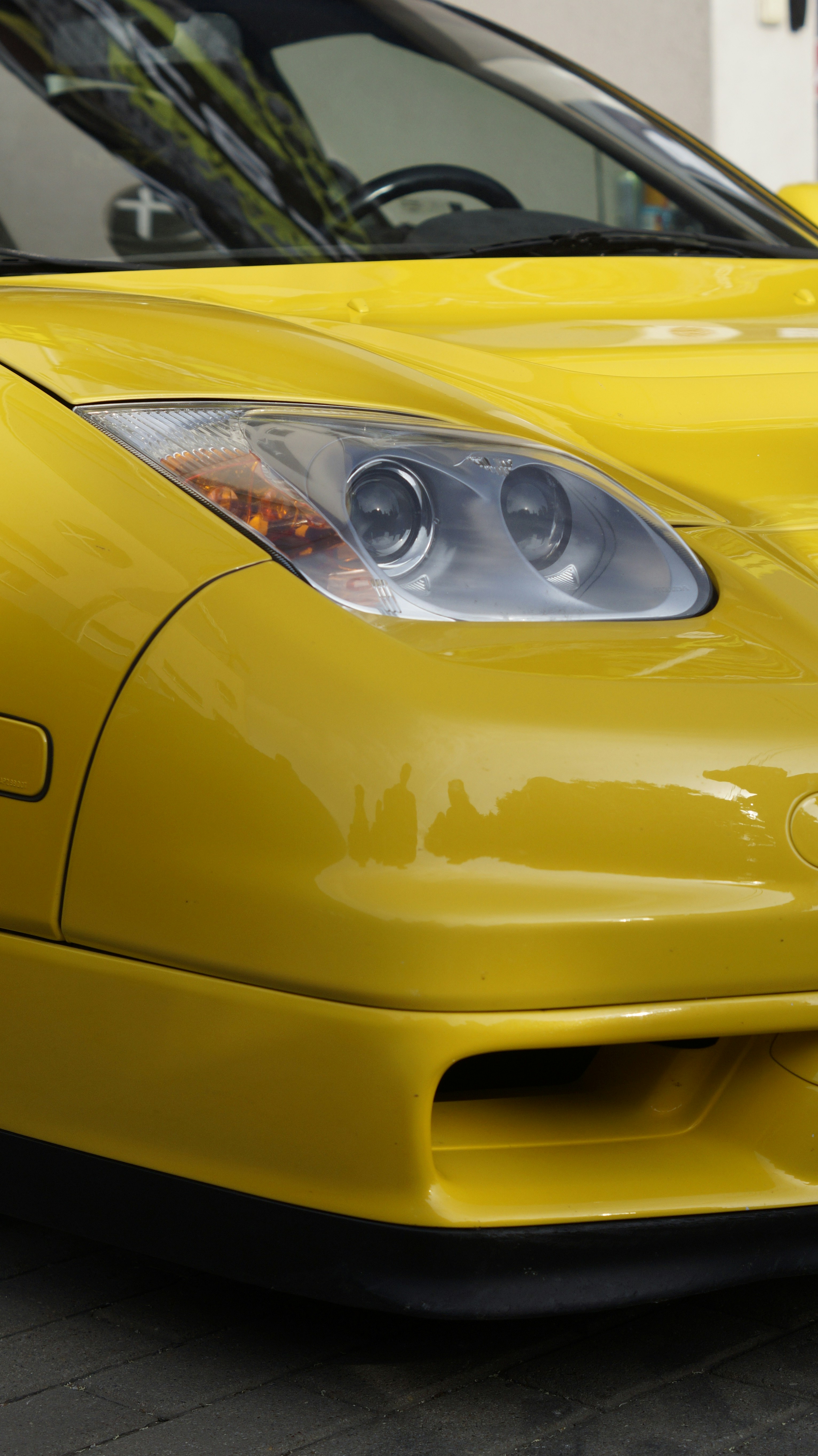 Close-up of a sleek yellow sports car showcasing its aerodynamic headlight design and glossy finish.