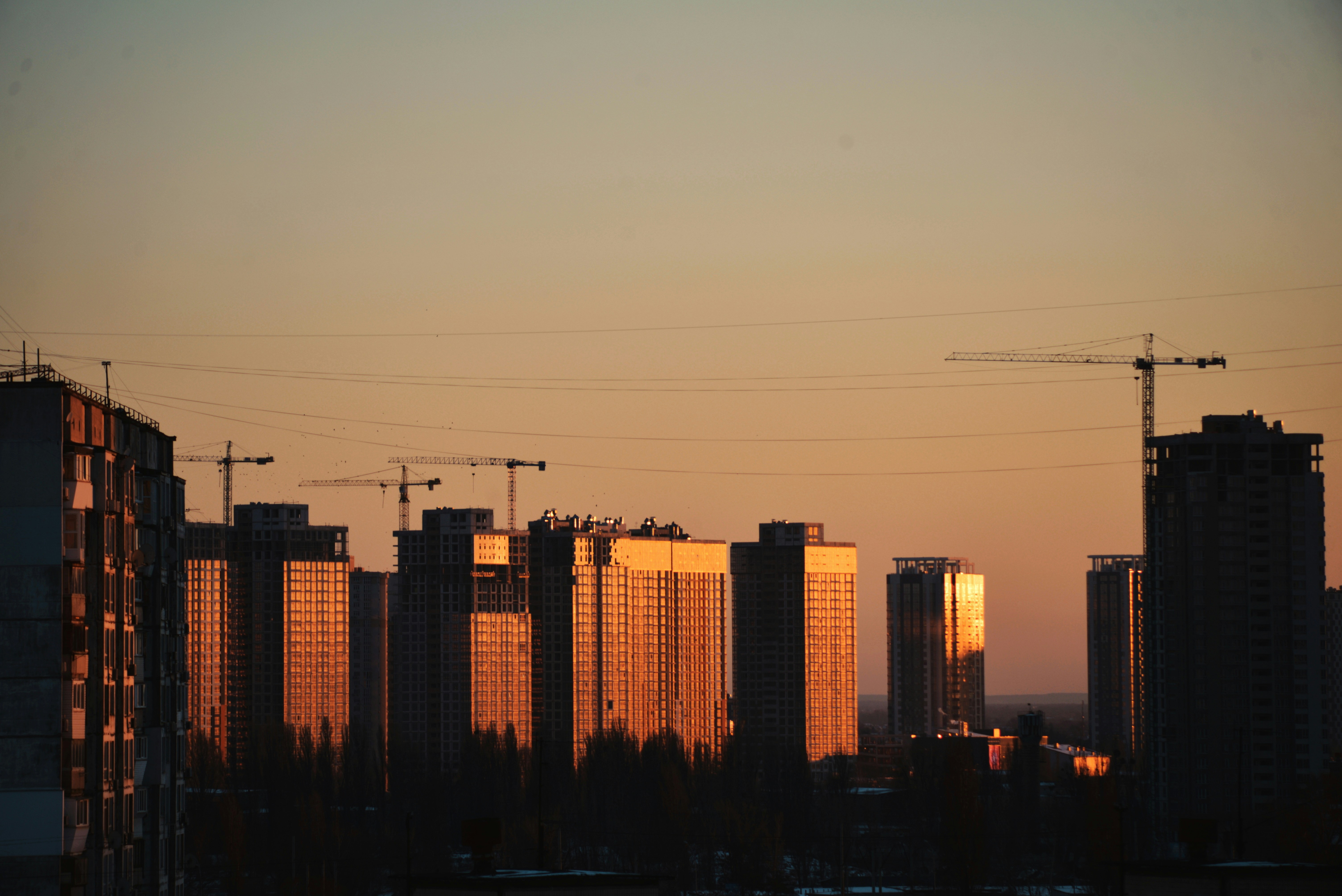 Crimson Horizon: Sunset Glow on a Crane-Lined Skyline