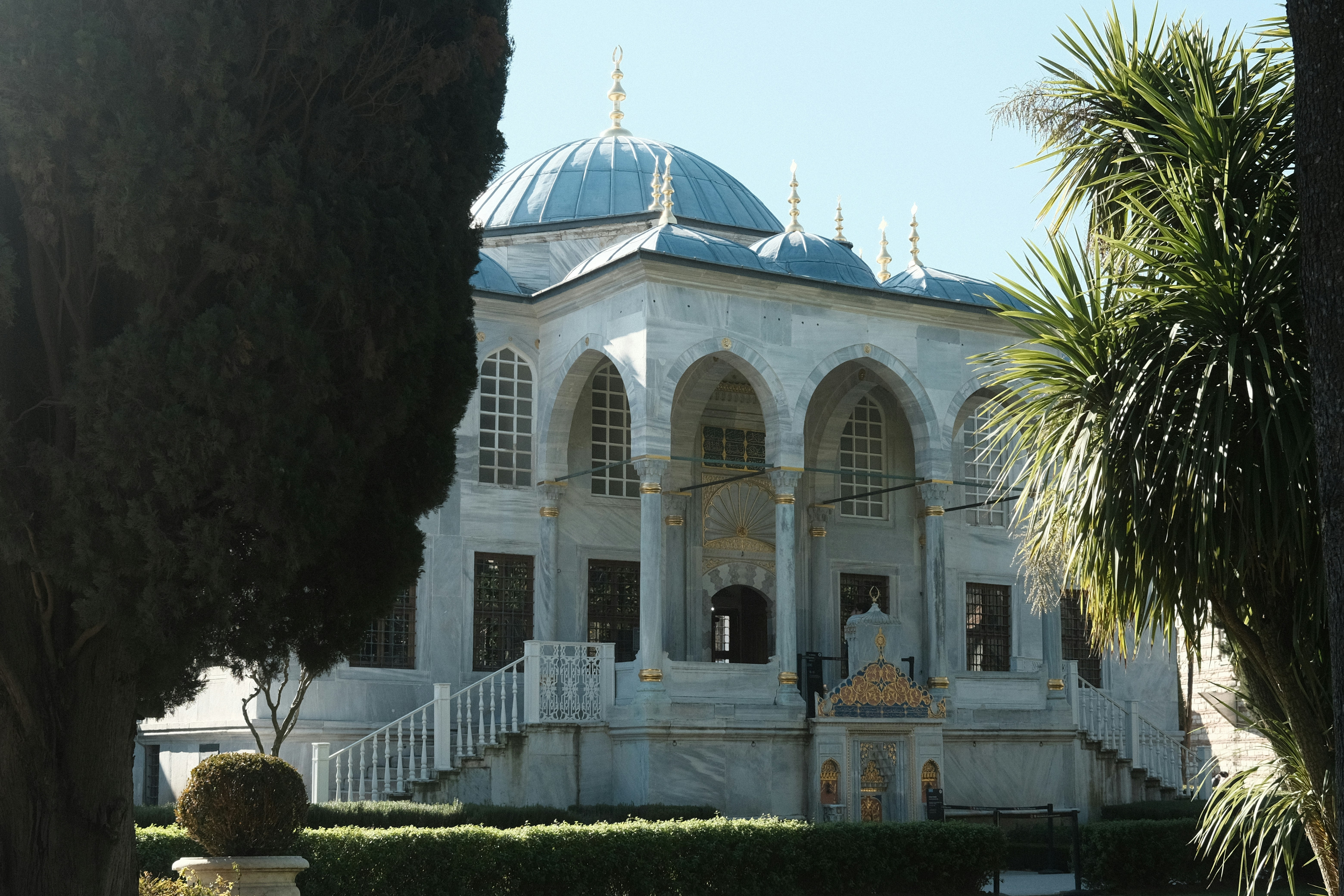 Azure-Domed Marble Pavilion Framed by Palms and Shadowed Foliage